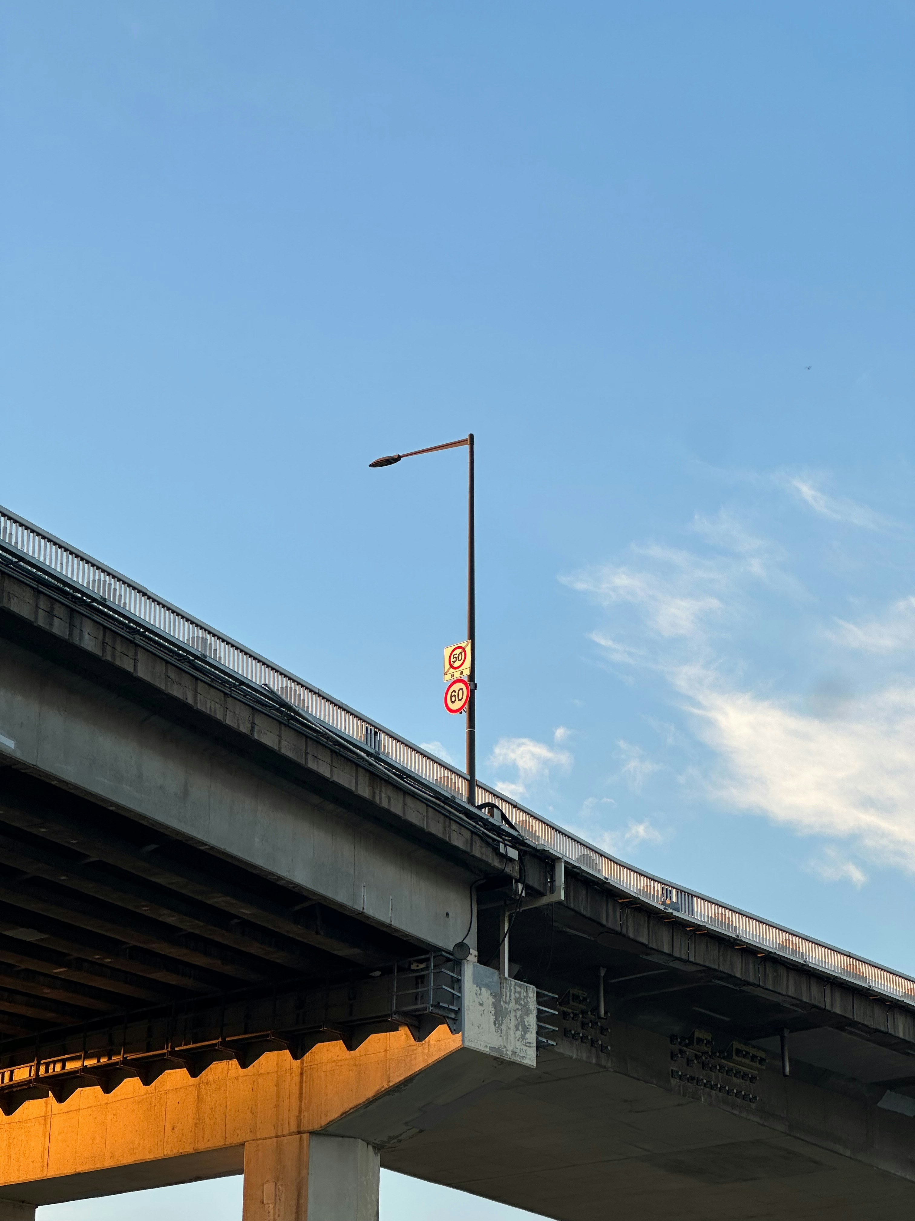 A concrete overpass with a streetlight and signs.