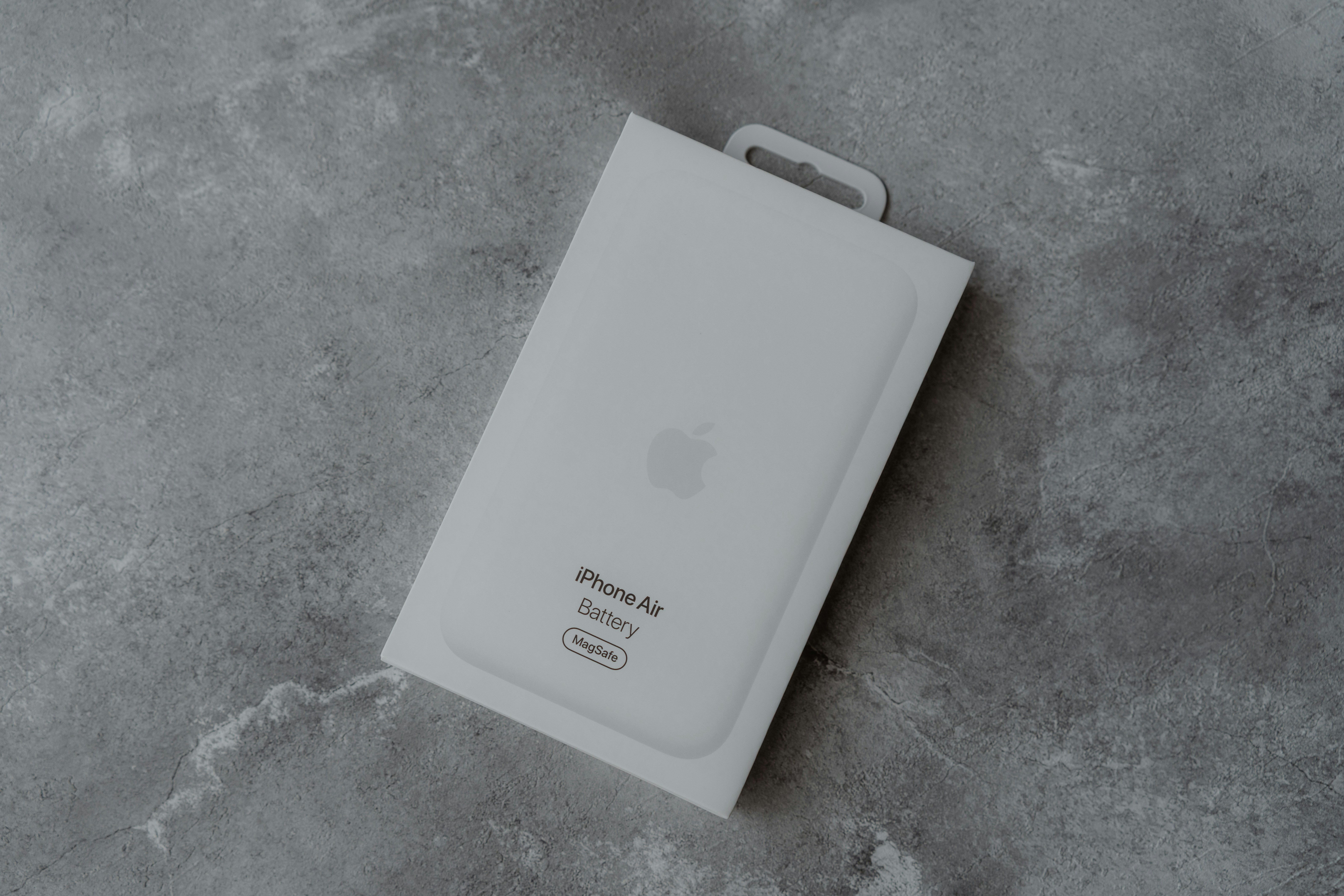 White iPhone case packaging on a gray textured surface.
