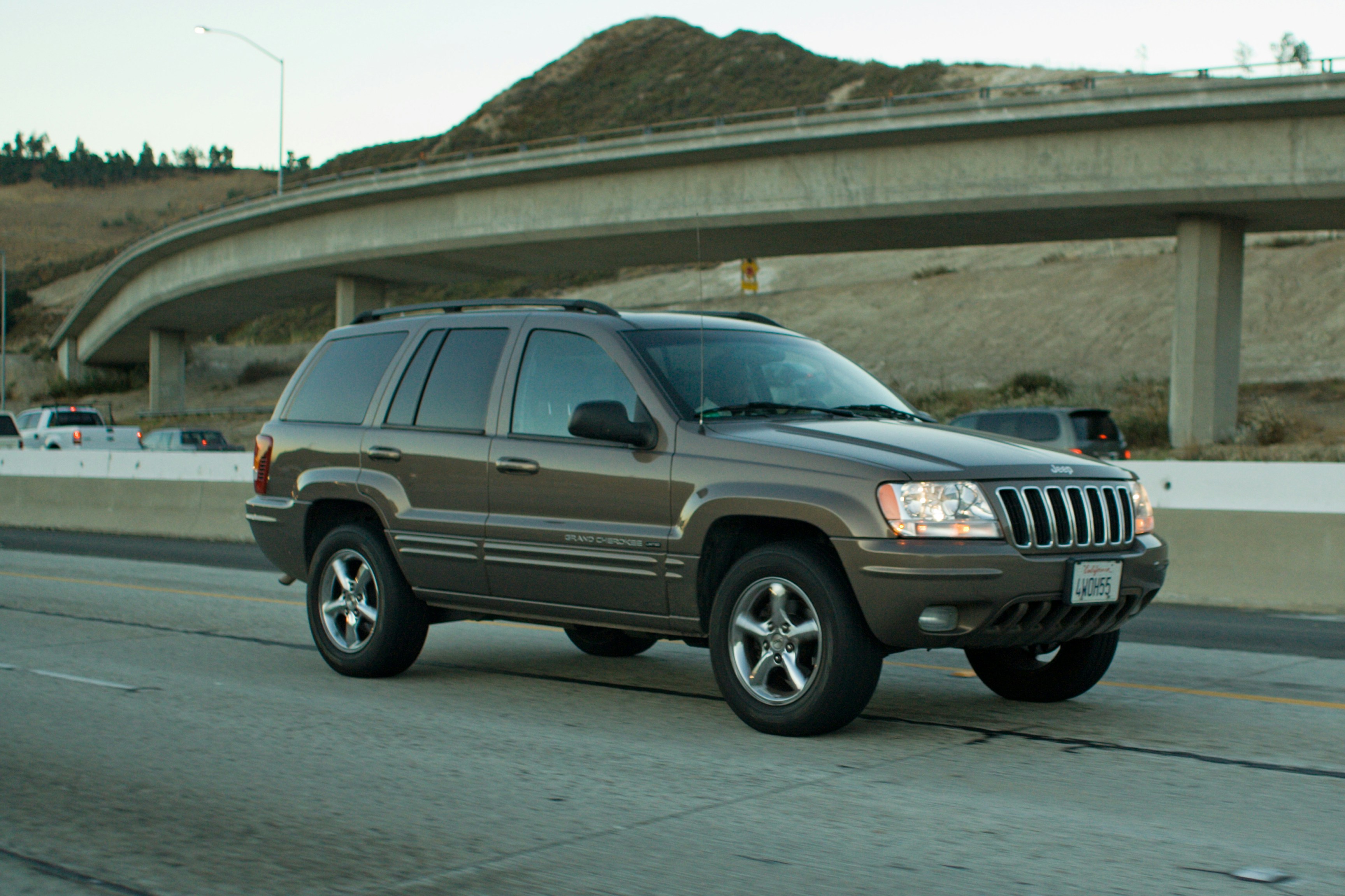 Brown jeep grand cherokee driving on highway