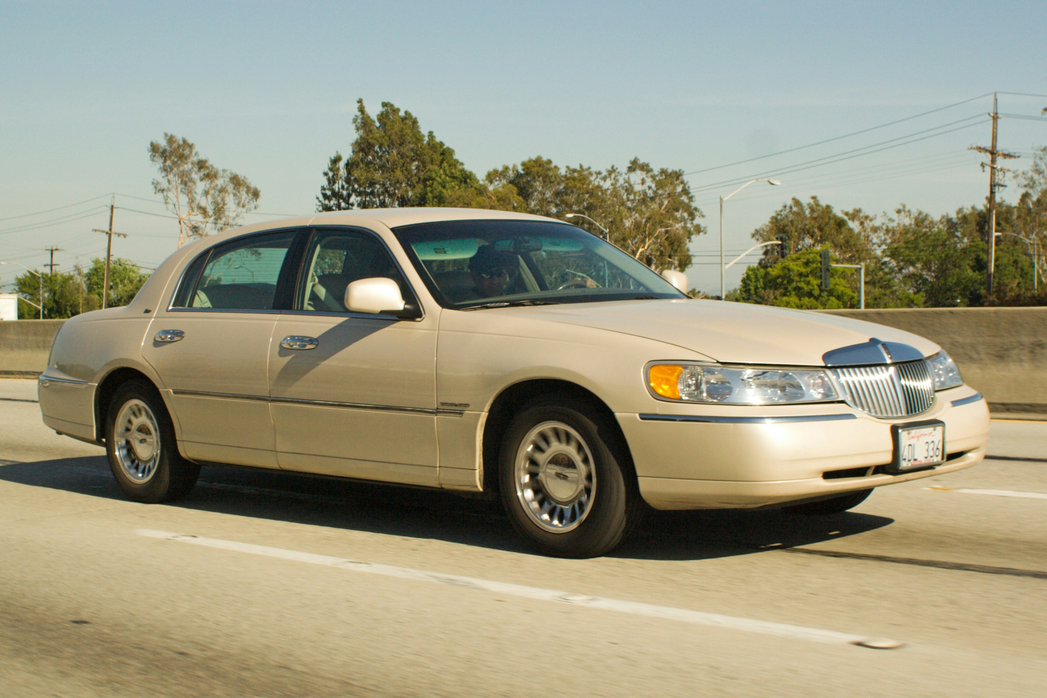 A tan sedan driving on a highway.