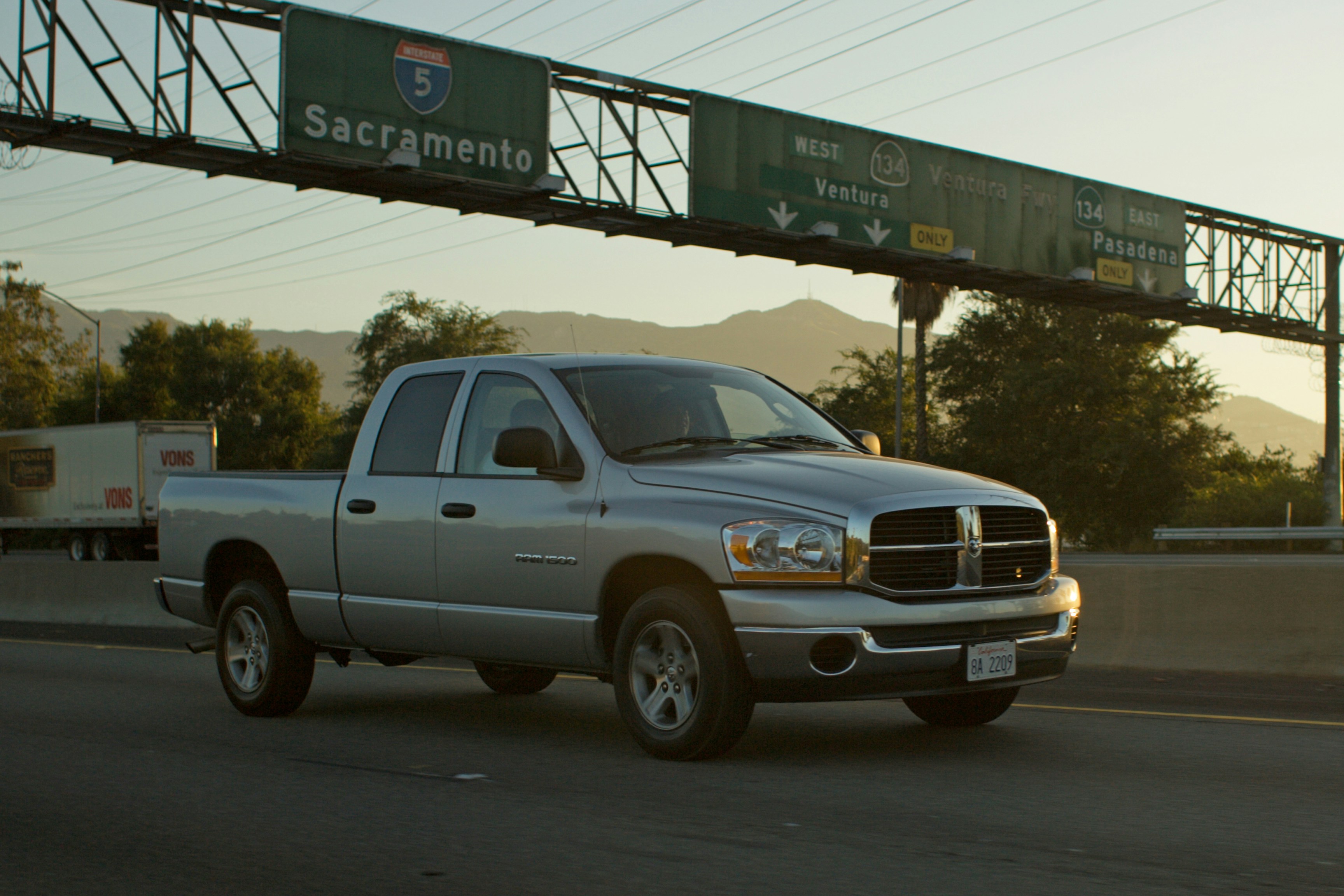 Silver pickup truck driving on highway under sign