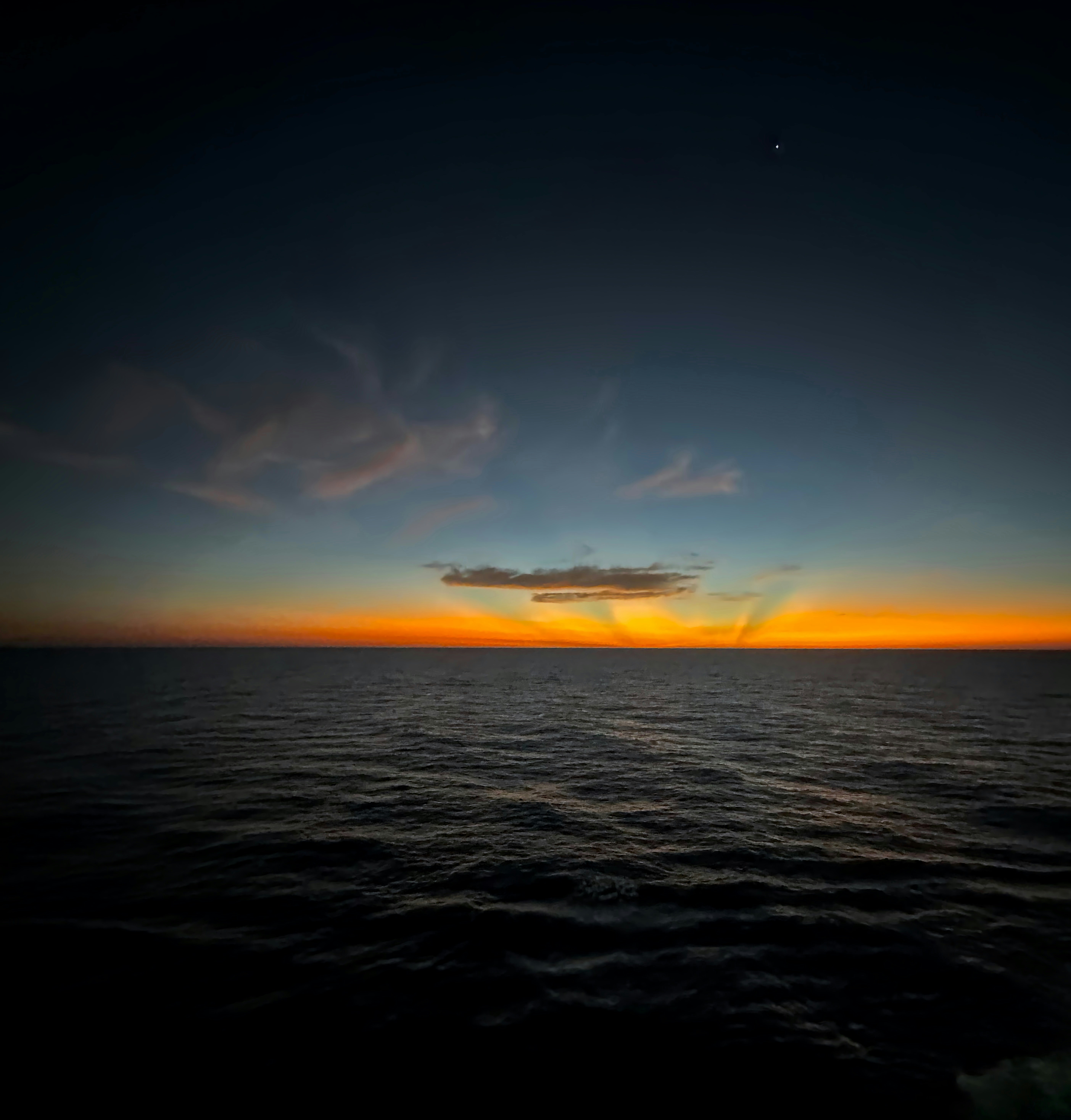 On the Pacific Ocean | Sunset over a calm ocean with a crescent moon.