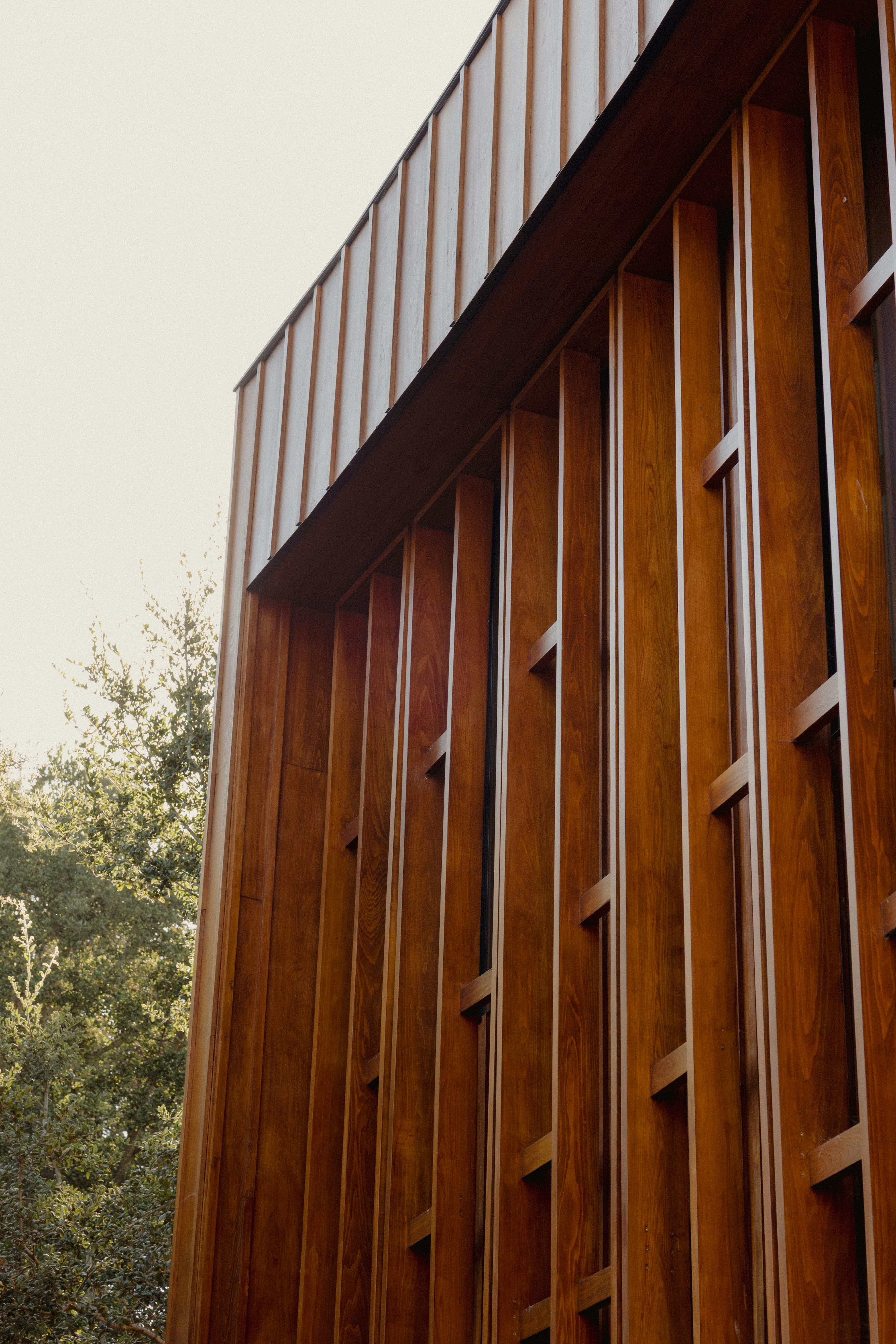 Vertical wooden slats create a rhythmic pattern against a soft, natural backdrop. The interplay of light and shadow enhances the architectural elegance.