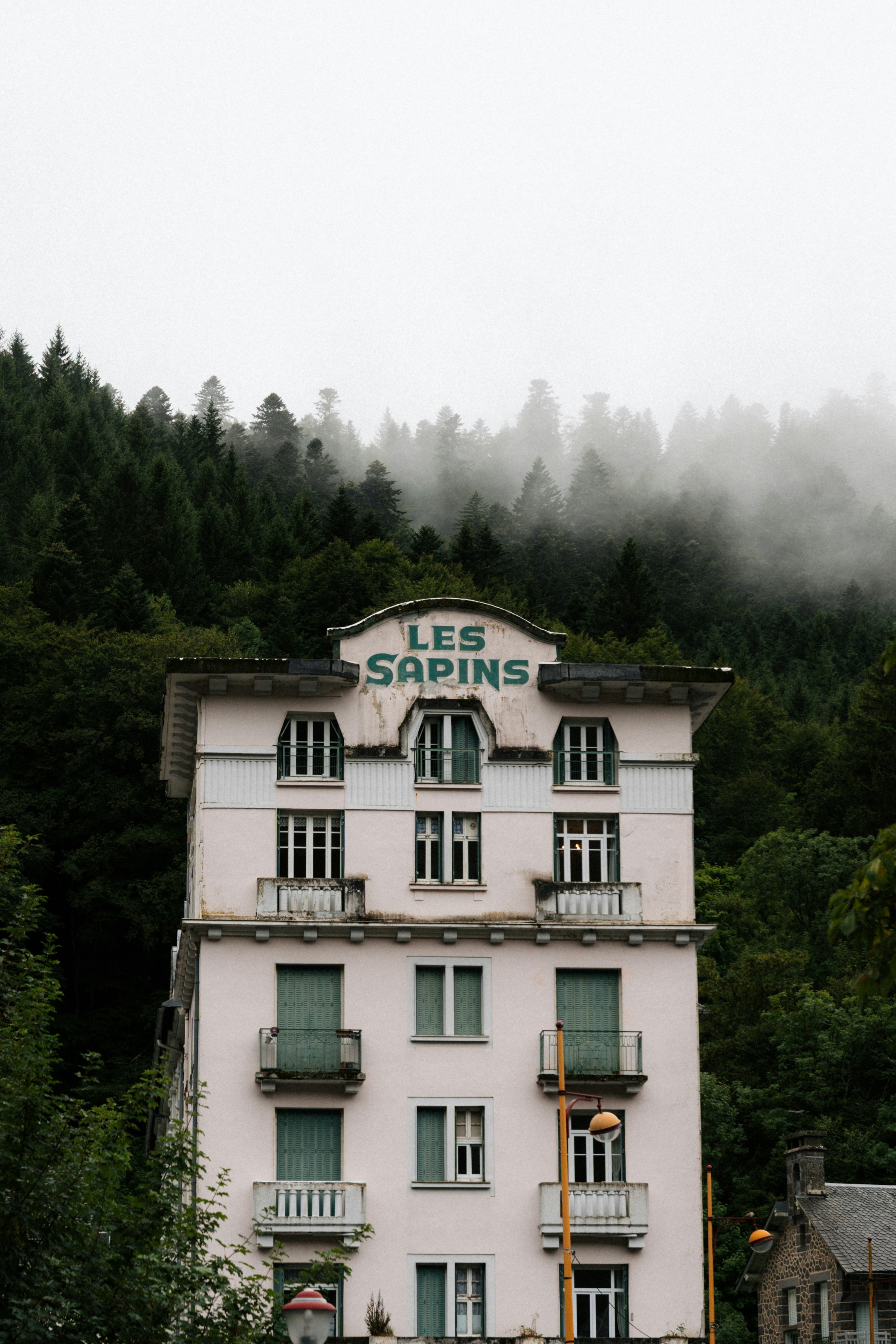 Old hotel building nestled in a misty forest.