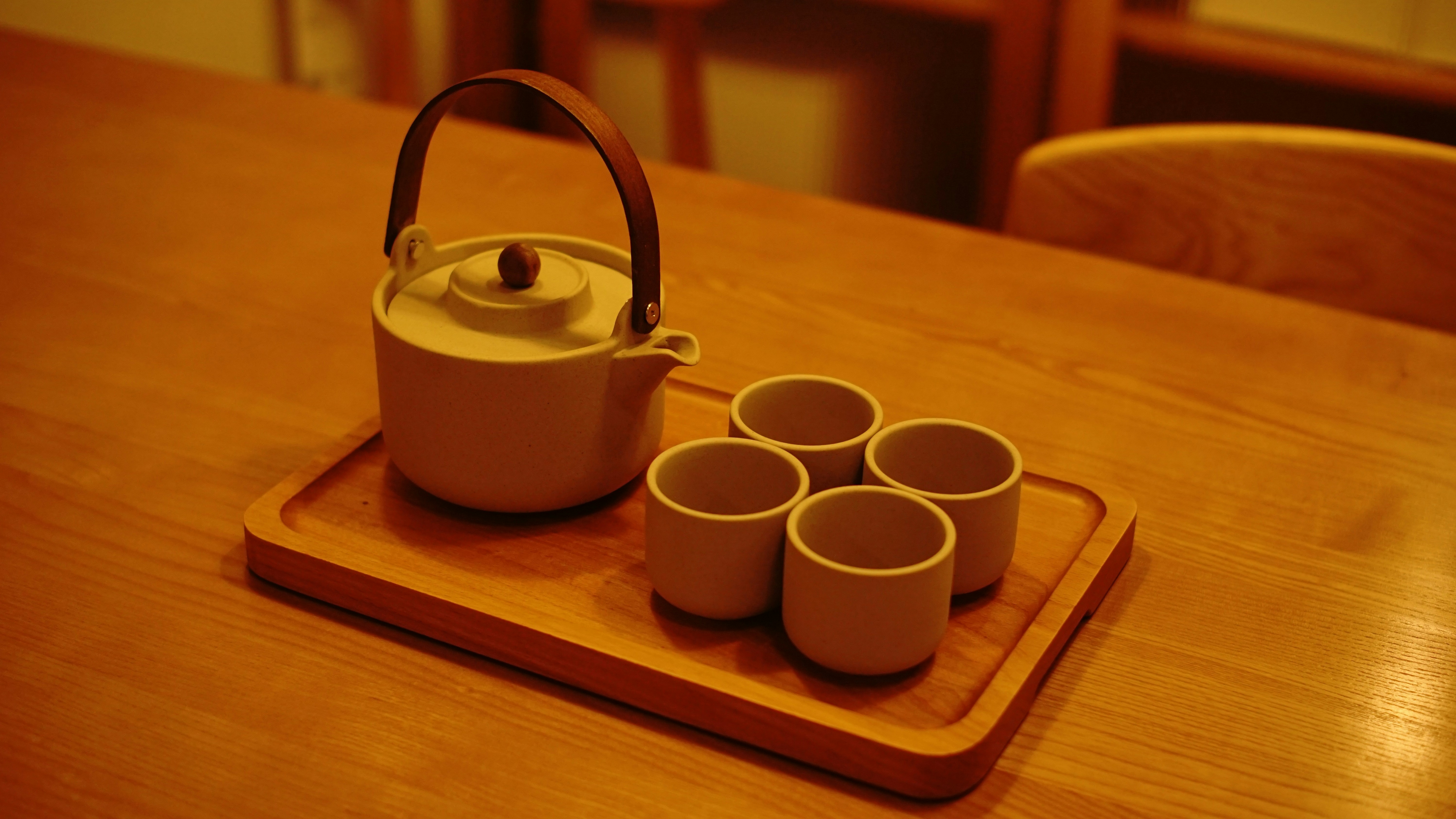 Tea set with teapot and four cups on wooden tray