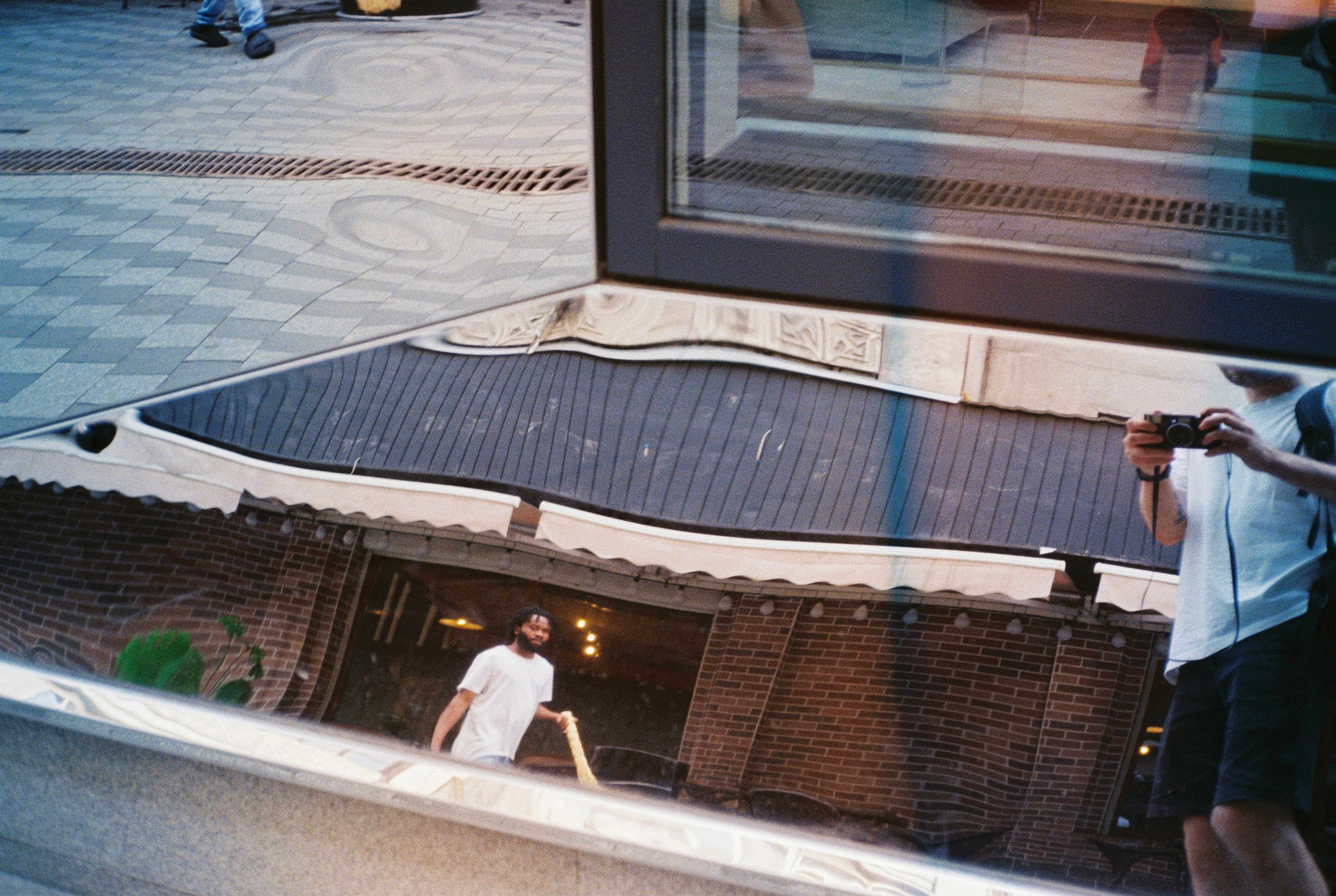 A man walks past a reflective surface, capturing the essence of city dynamics and everyday moments. The scene showcases a blend of architecture and human presence.