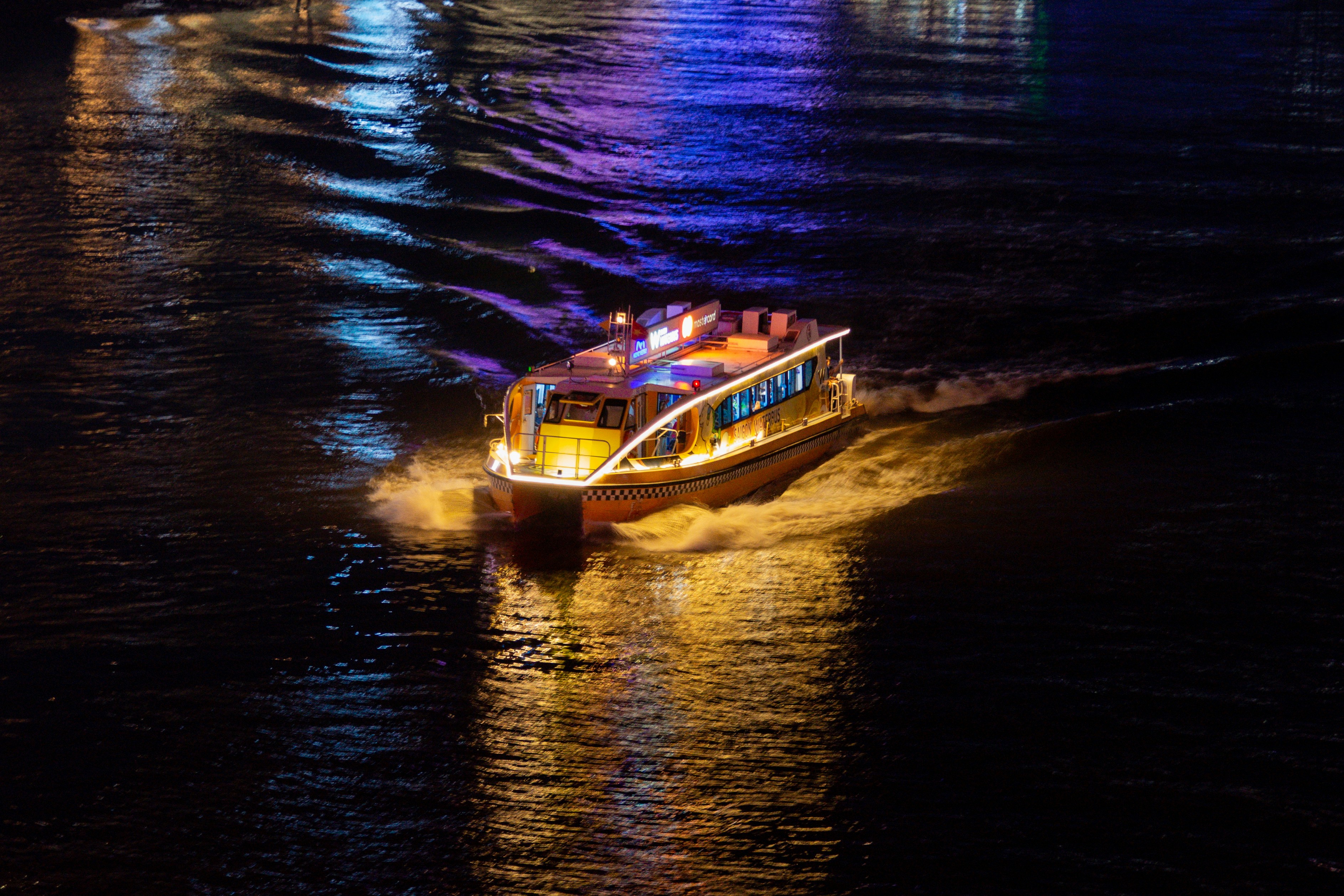 Neon Wake: A Night Boat Carves Golden Ripples Across Velvet Water
