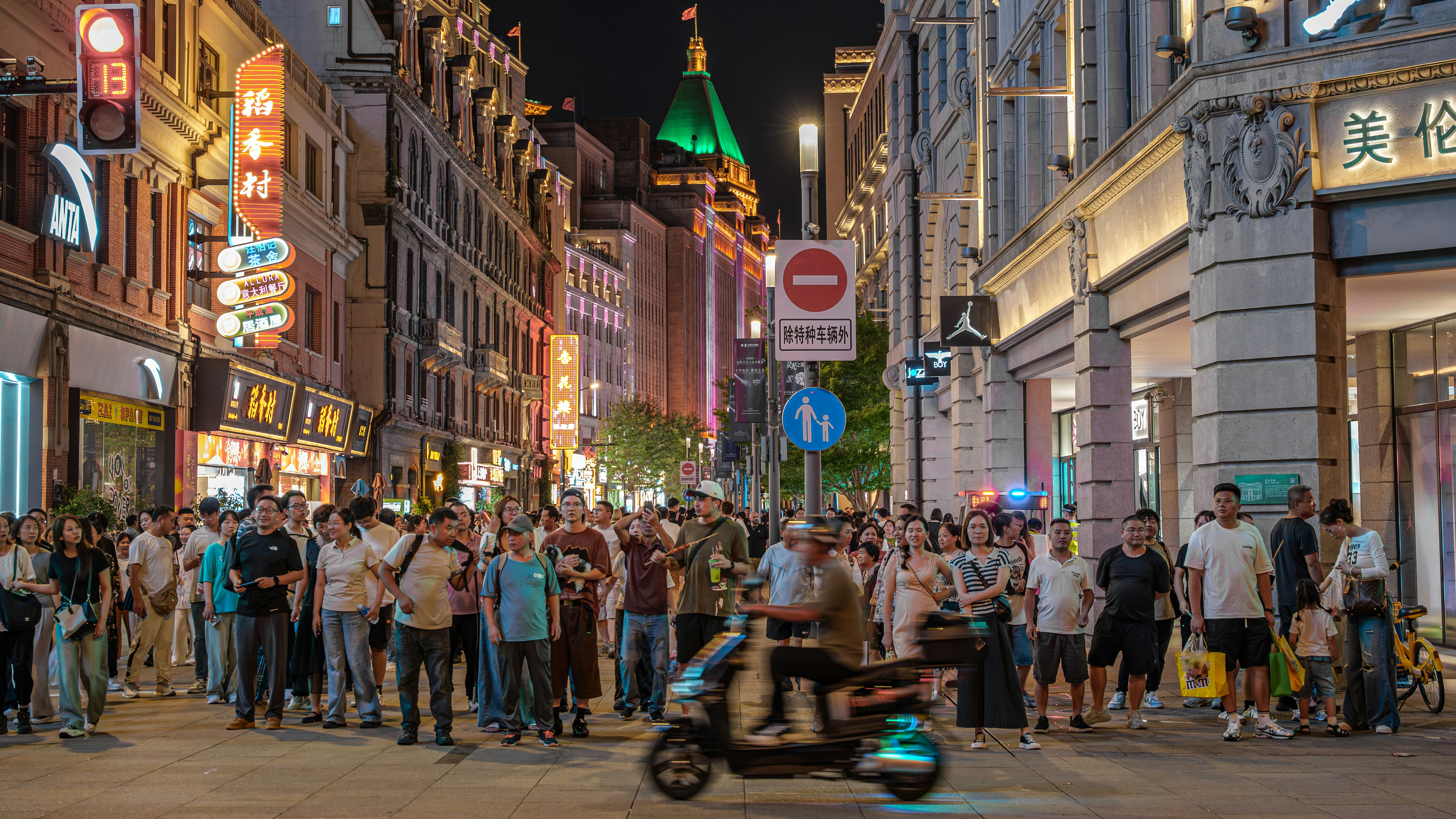 Bustling street scene at night, filled with pedestrians and illuminated storefronts, showcasing the vibrant life of the city.