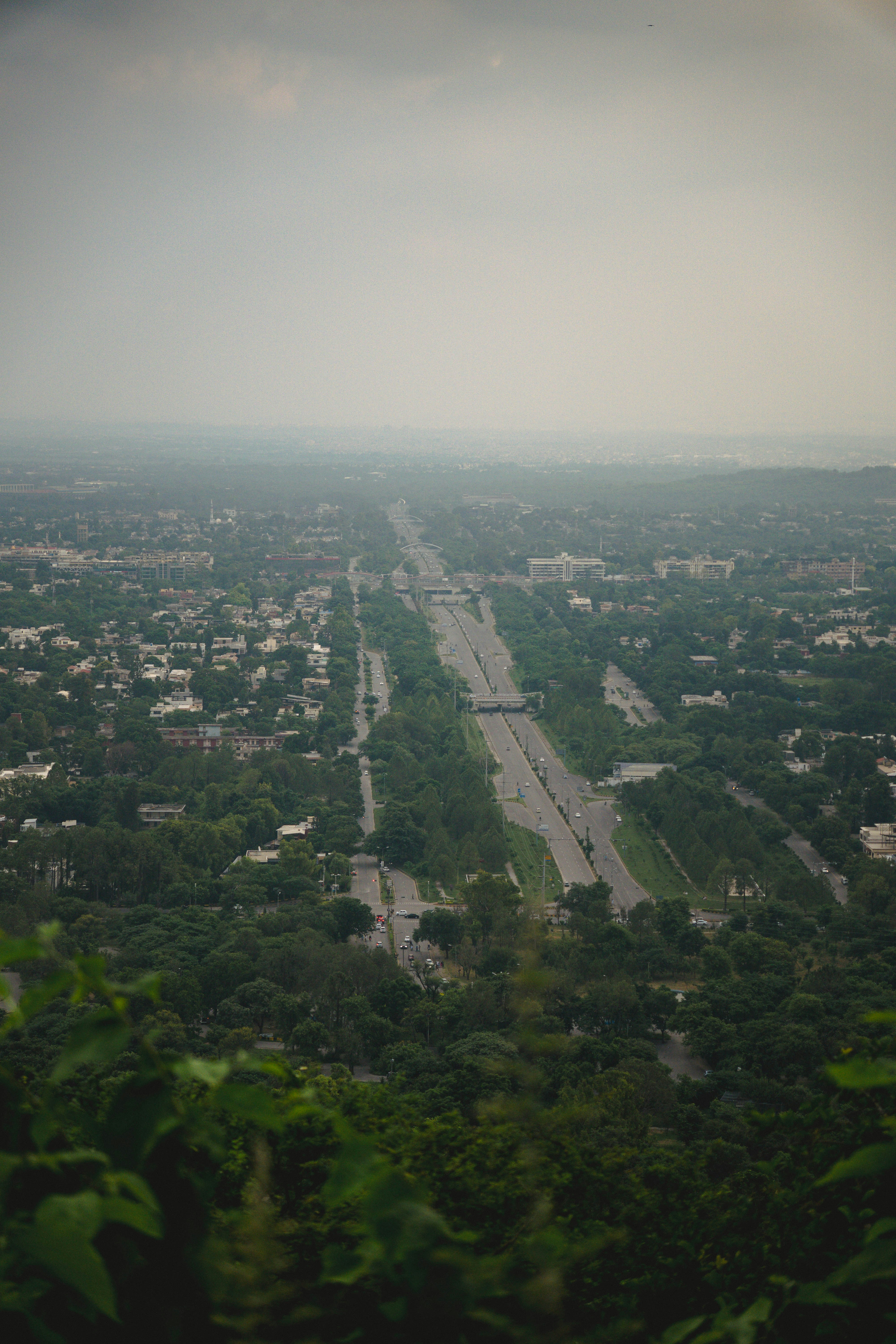Aerial view of a wide highway through a green cityscape.