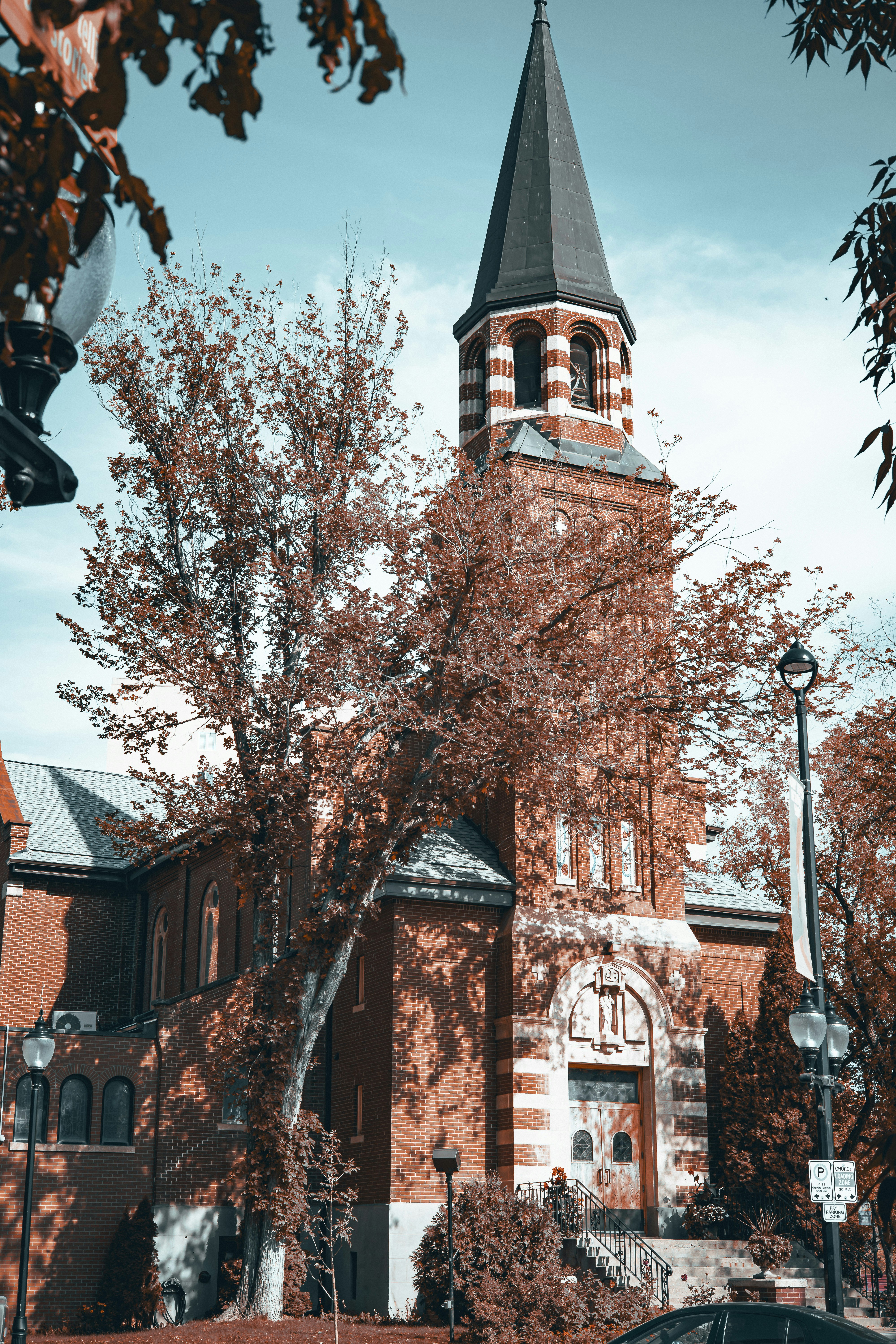 Brick church with tall steeple and autumn trees