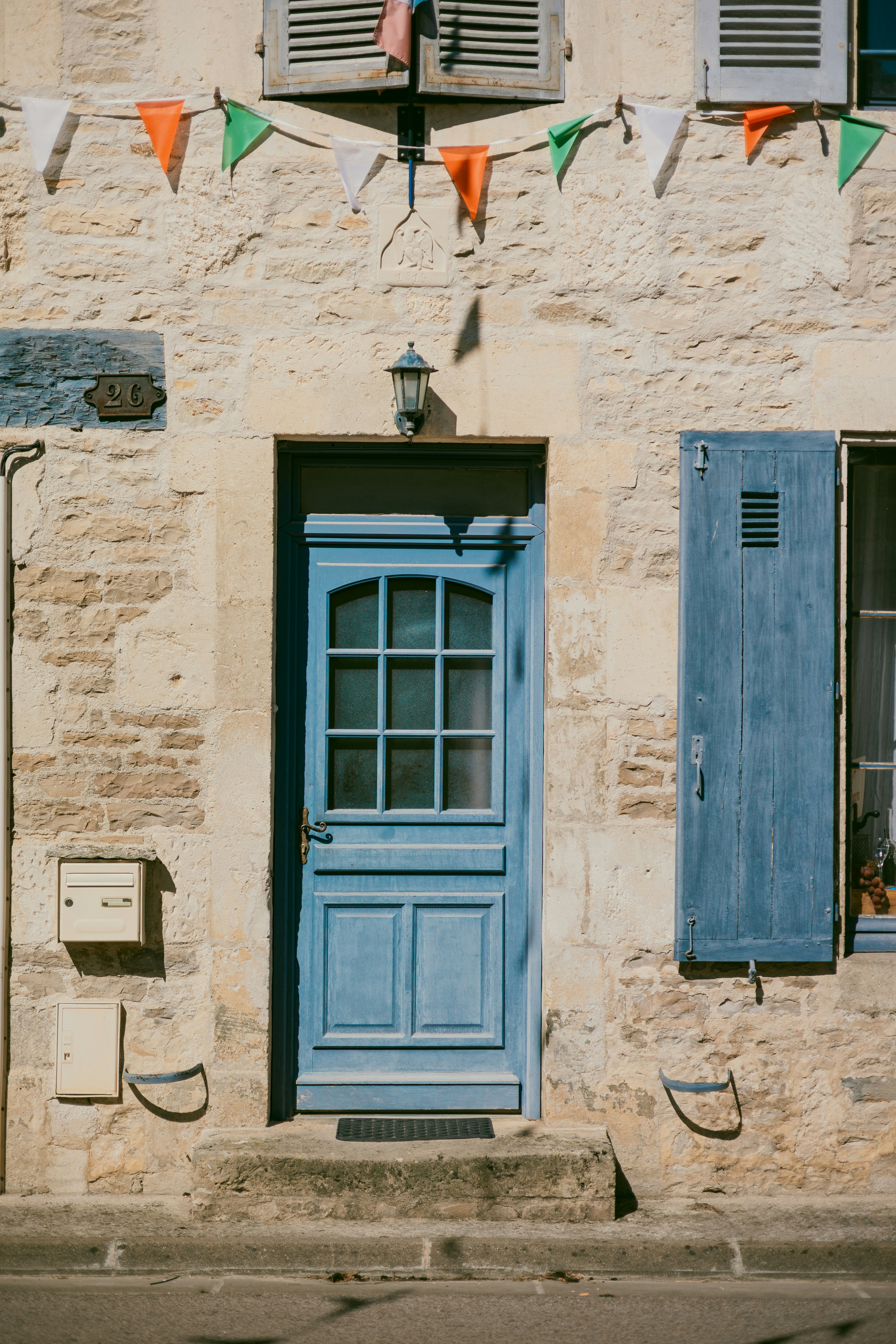 A rustic blue door on a stone building with flags.