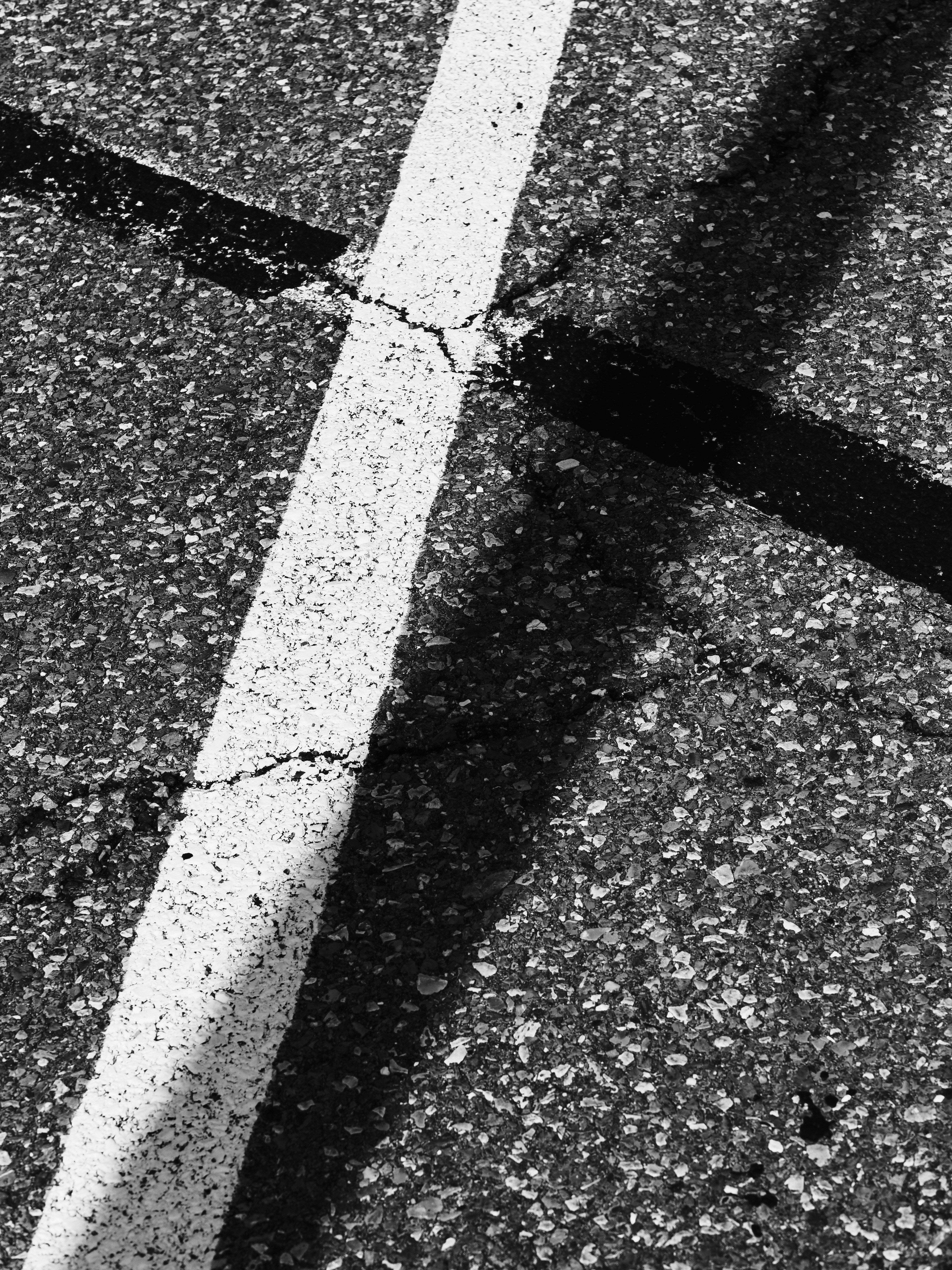 Cracked white line on asphalt with shadows