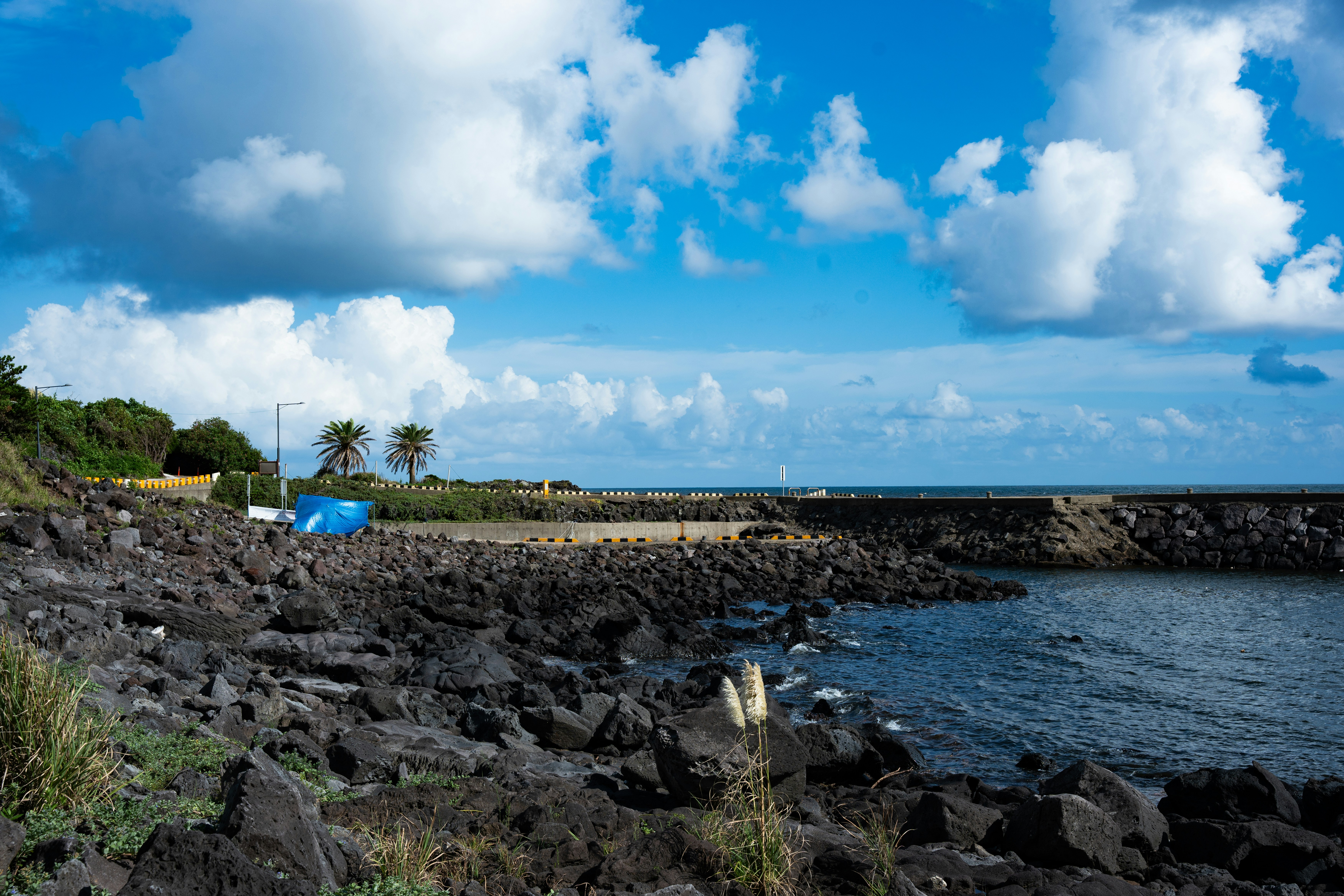 Rocky coastline with blue sky and fluffy clouds.