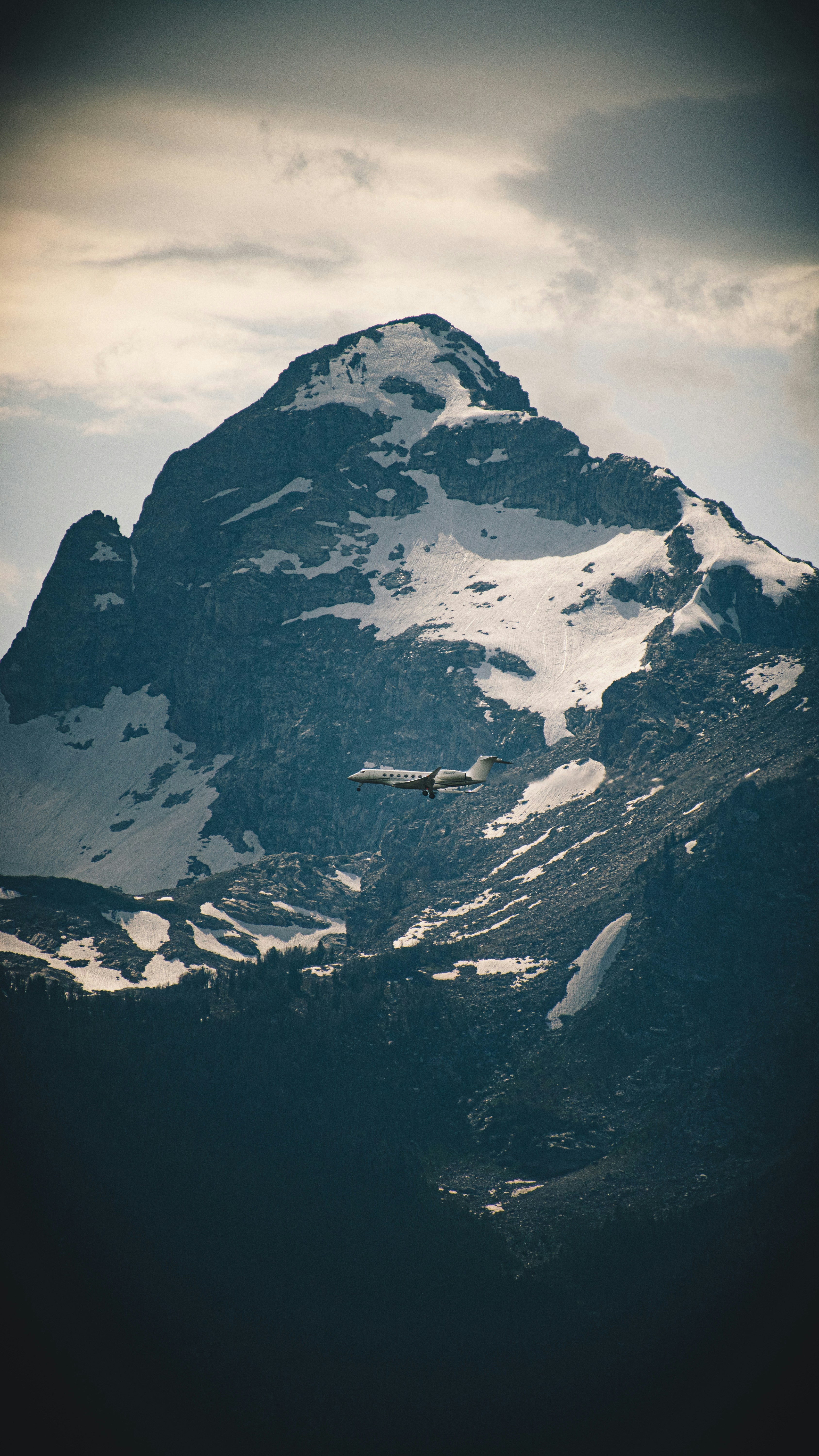Airplane flying past a snow-capped mountain peak.