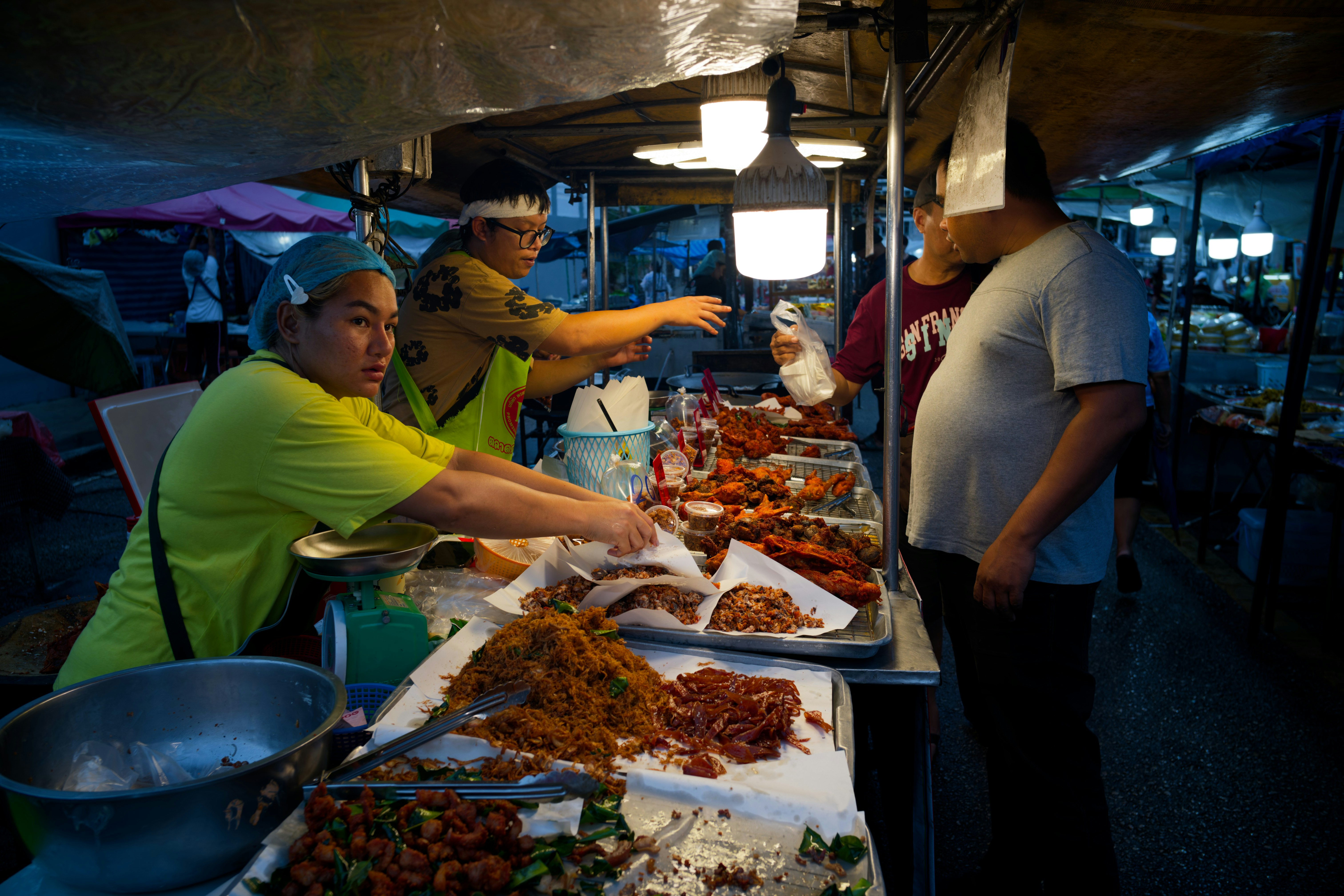 Vibrant street food market scene with vendors serving a variety of dishes under warm lights, creating an inviting atmosphere.