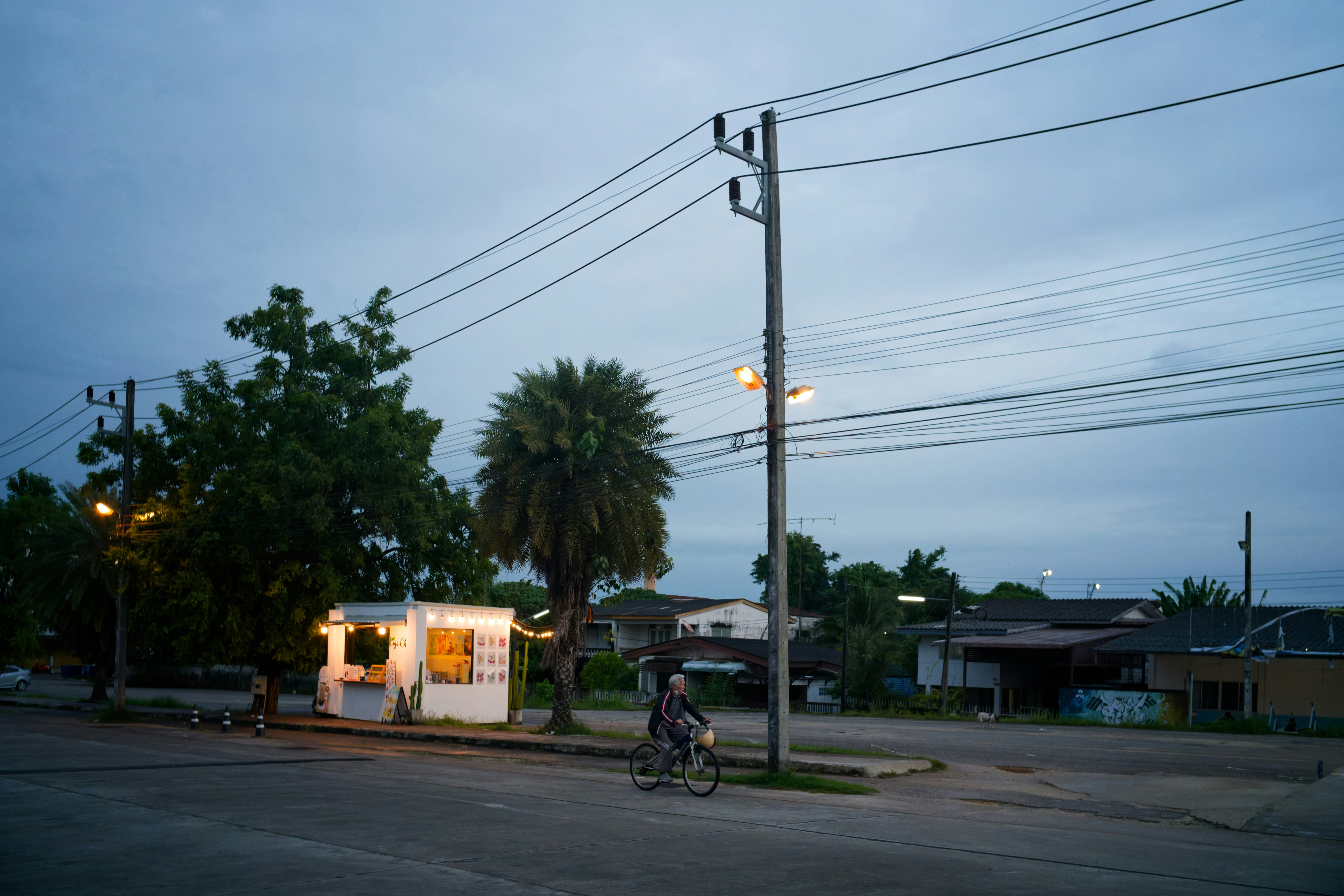 Street scene with power lines and small building at dusk.