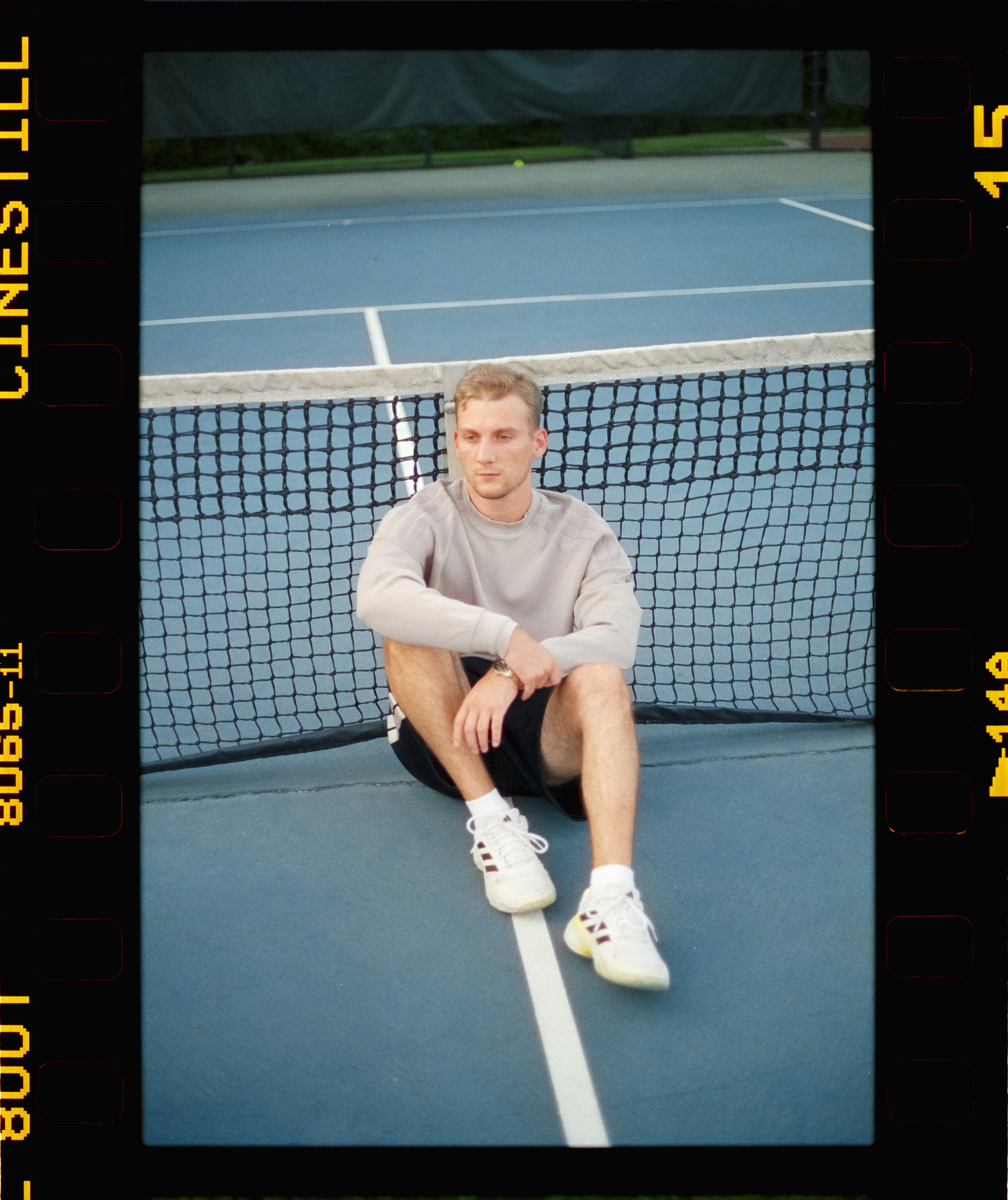 Man sitting on a tennis court near the net