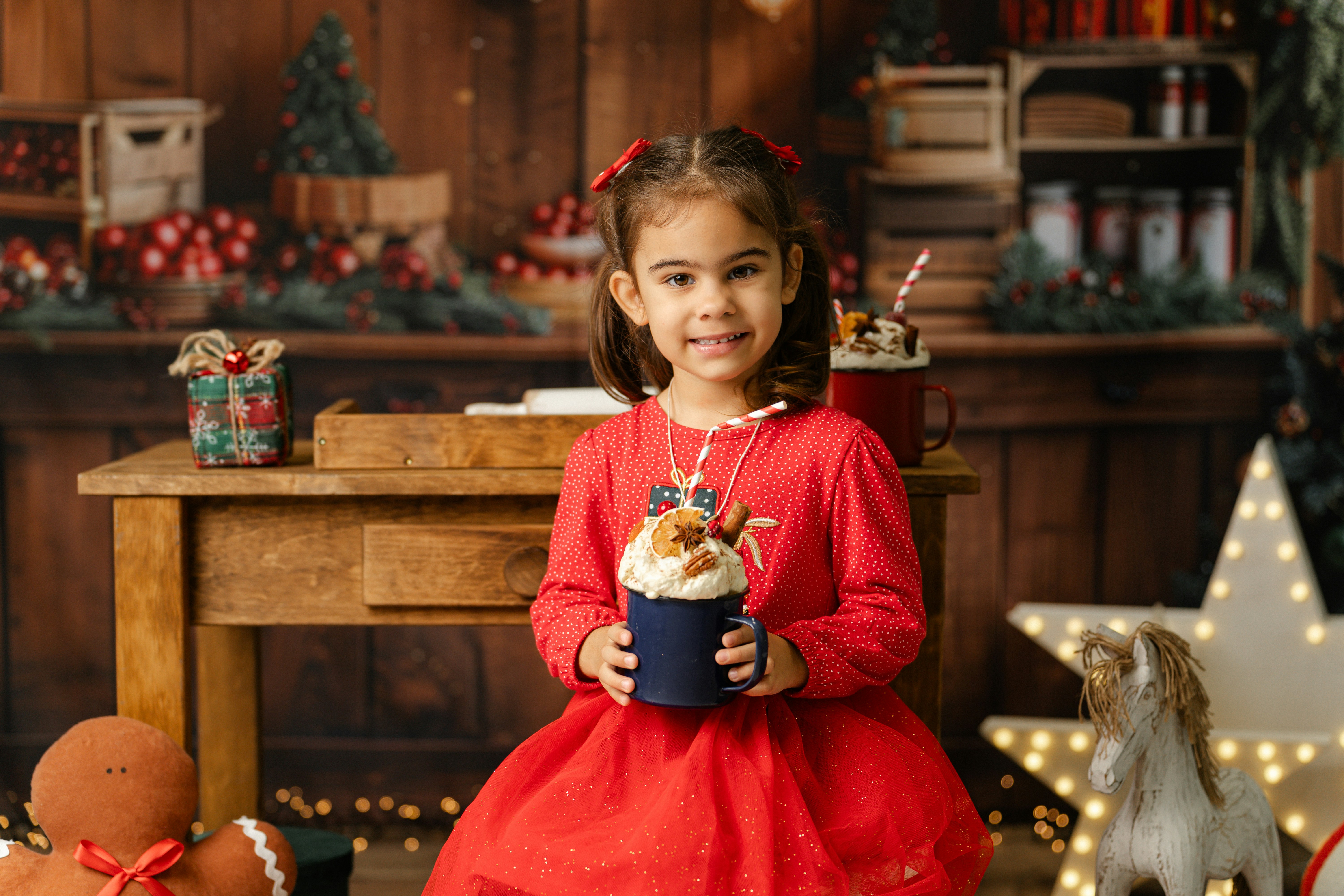 Young girl in red dress holds festive holiday drink.