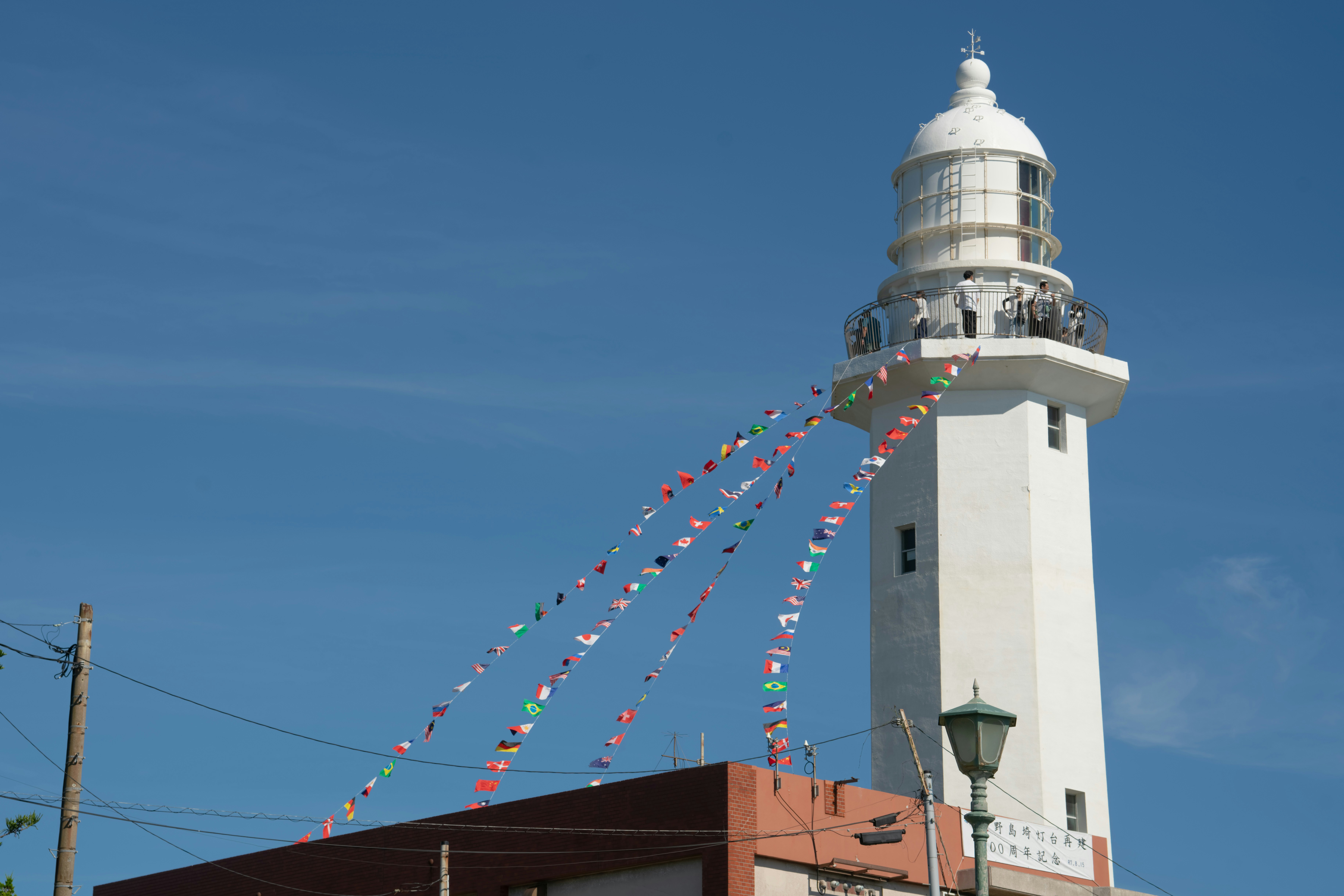 Flags on a Coastal Beacon: A Lighthouse under a Clear Sky