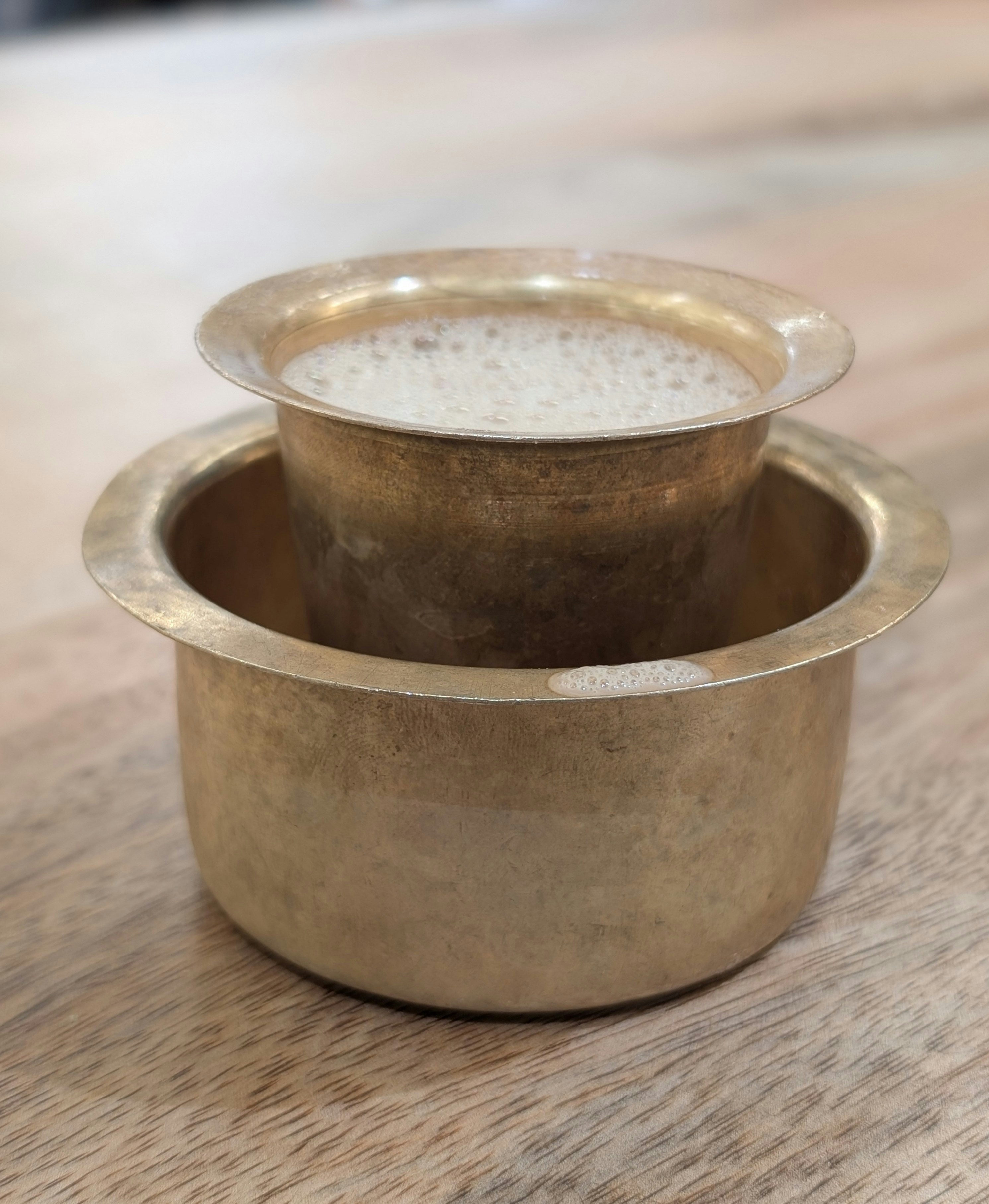 Traditional brass filter coffee maker with frothy coffee