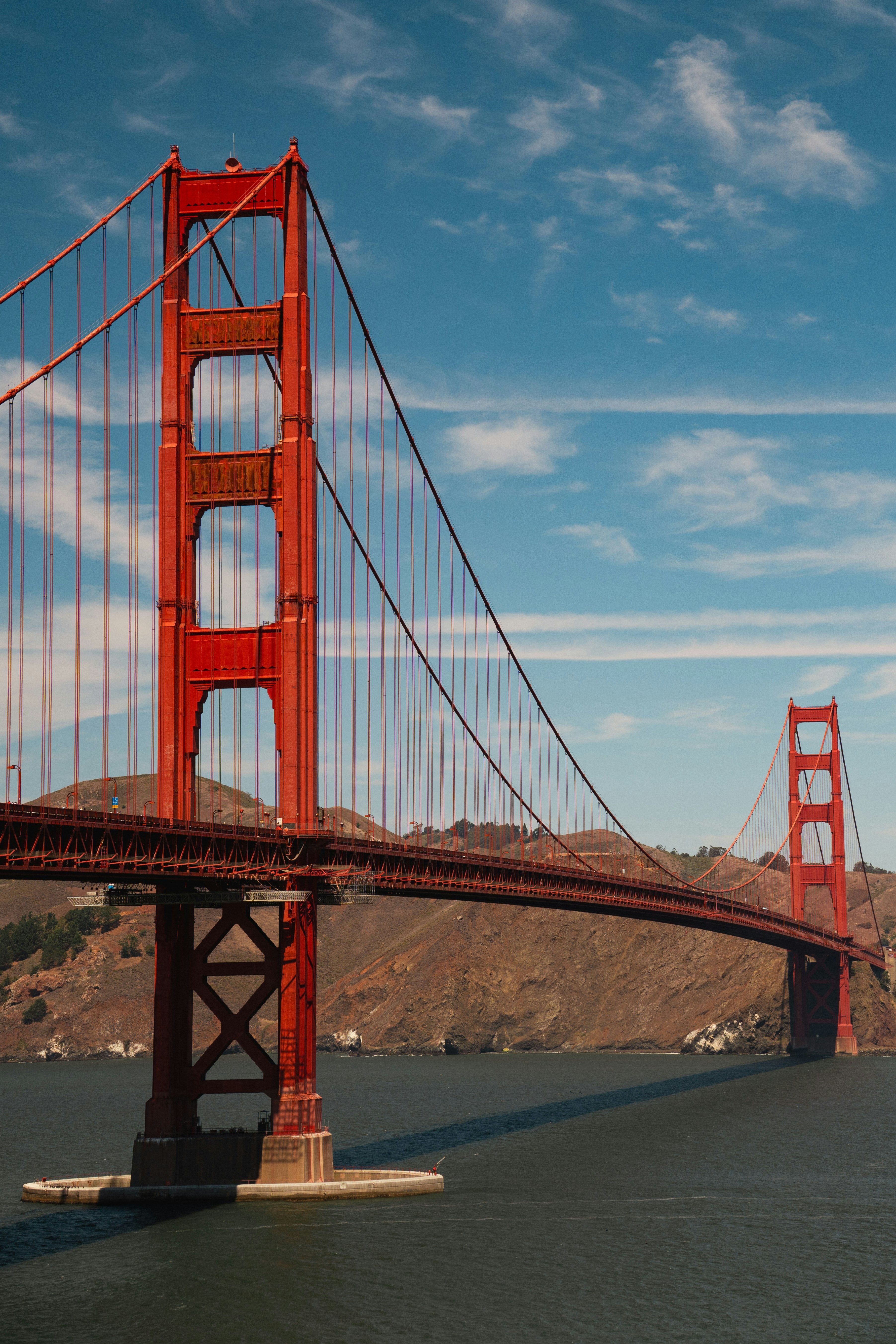 Iconic Golden Gate Bridge towering over the bay, framed by a clear blue sky and distant hills. The vibrant red structure stands as a symbol of engineering marvel.