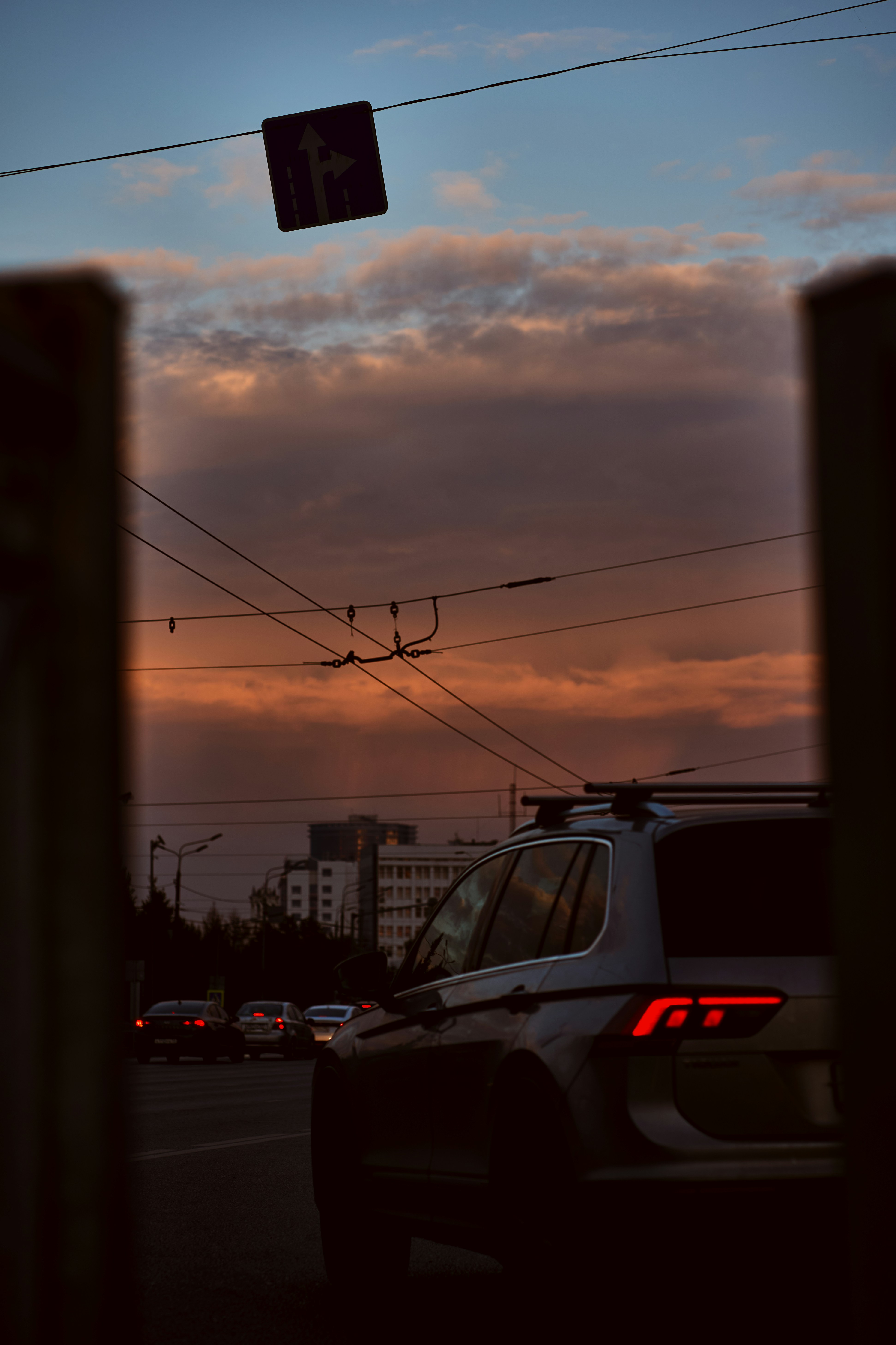 Car driving on street at sunset with clouds.