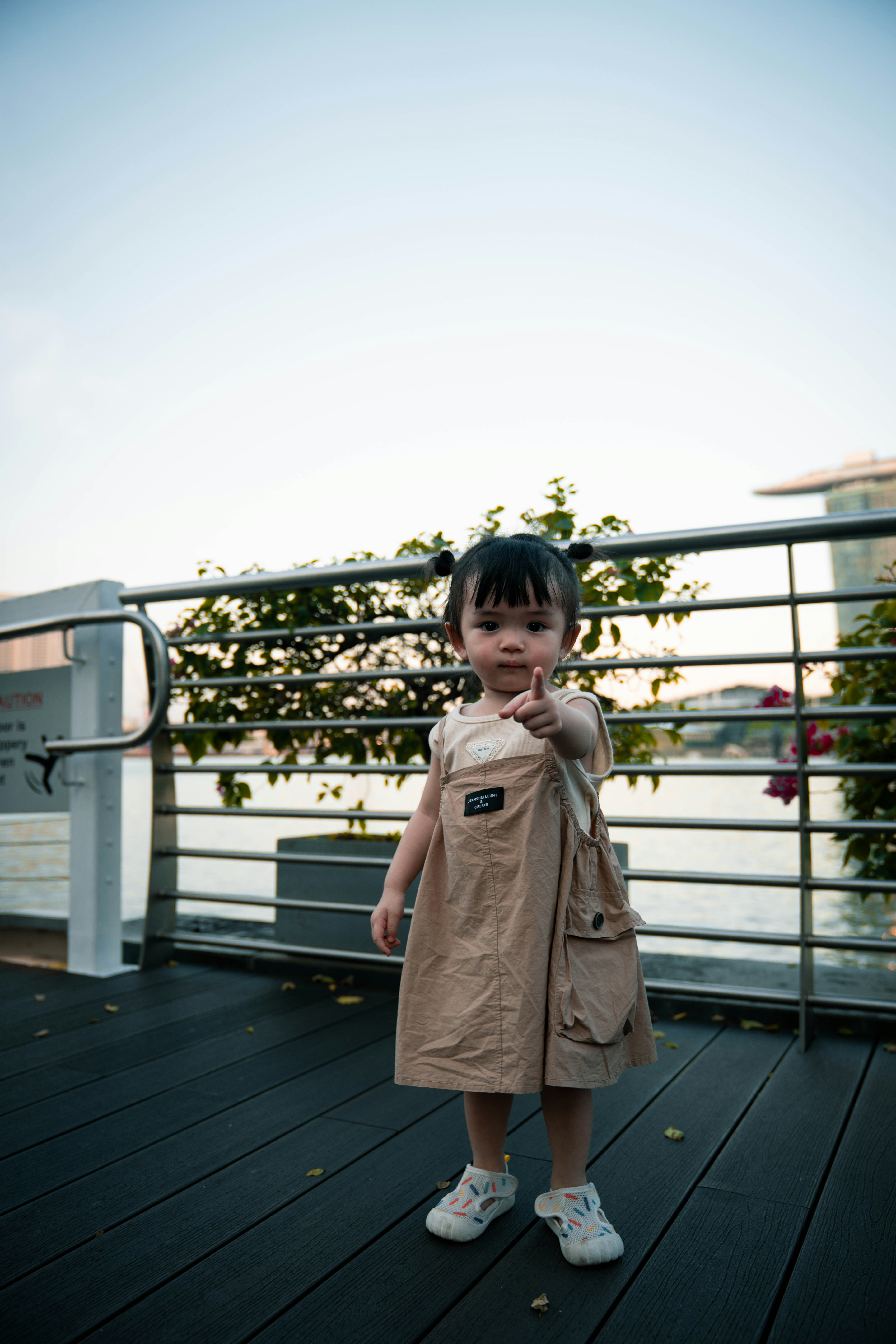 Young girl in a dress gives a thumbs up.