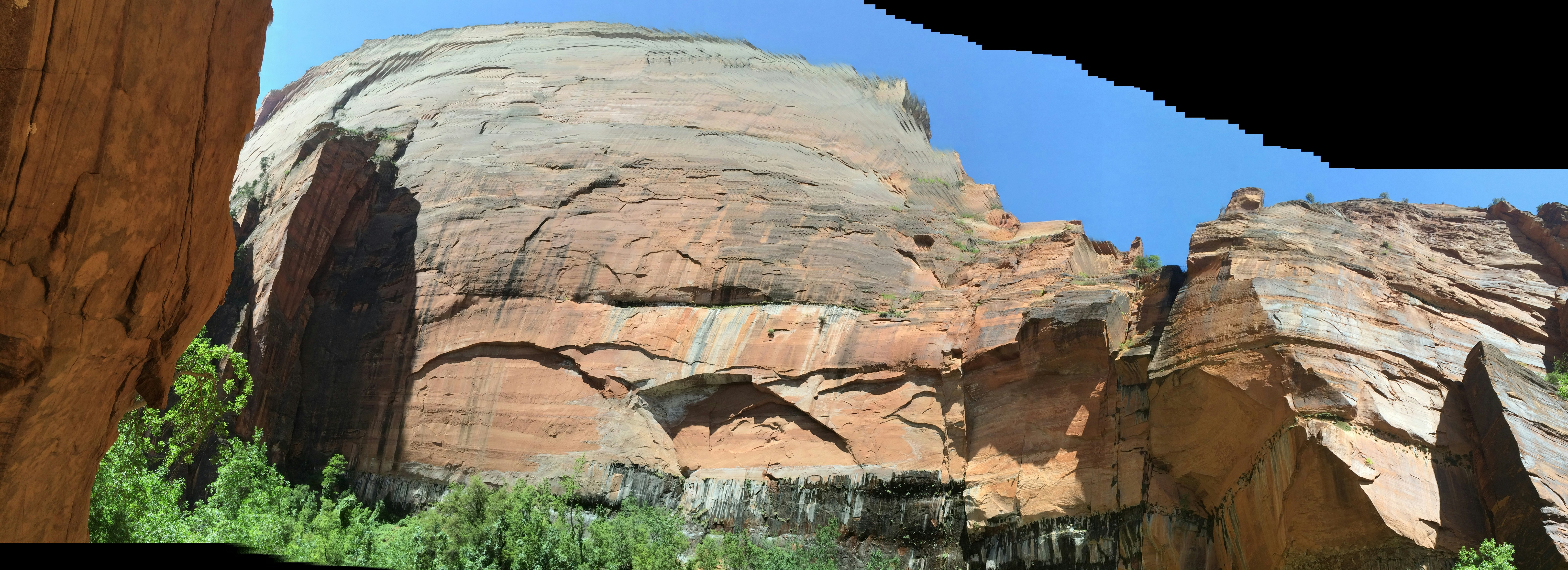 Panoramic view of towering red rock cliffs surrounded by lush greenery, showcasing the grandeur of nature's architecture.