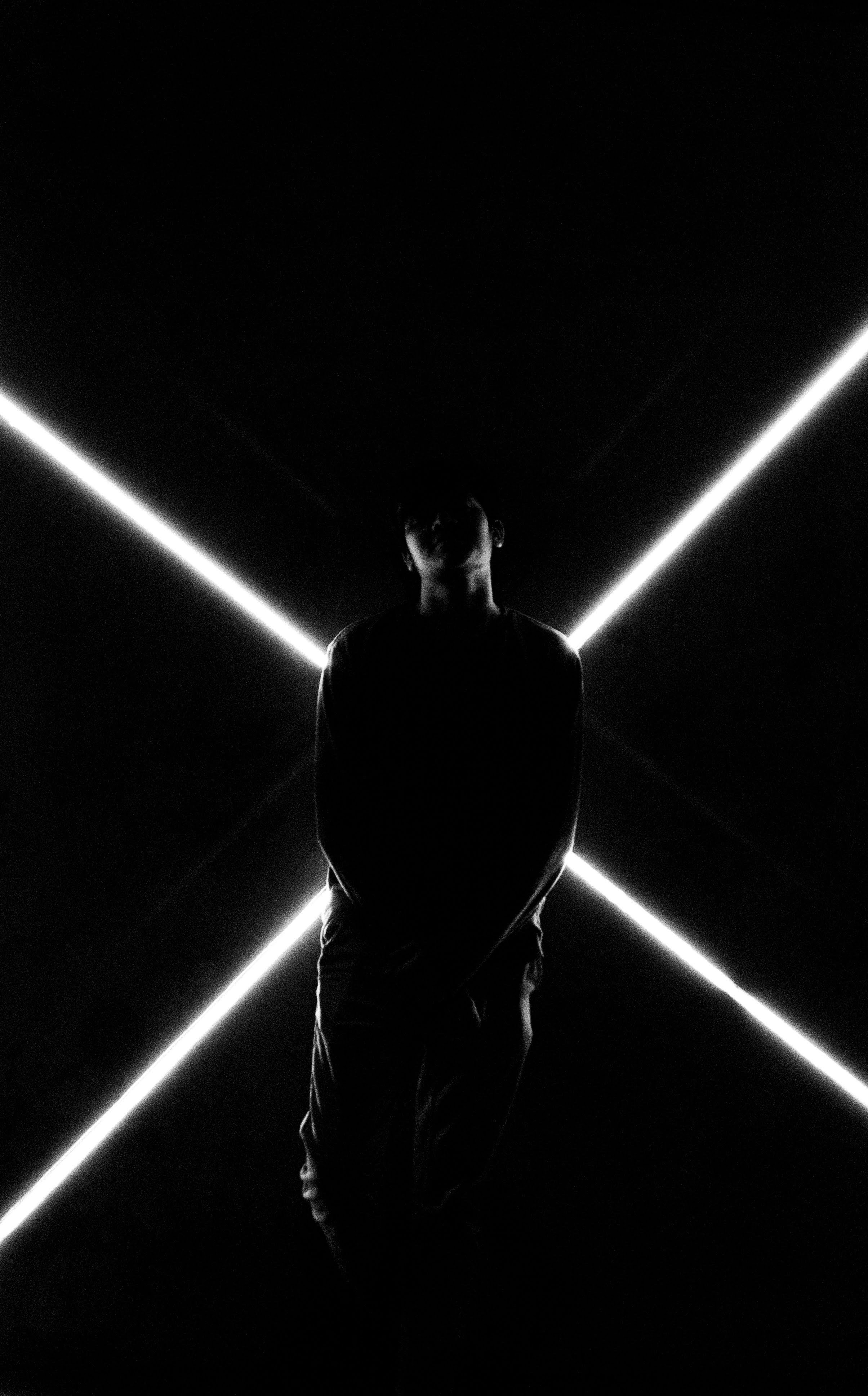 Silhouette of a person against glowing x-shaped lights.