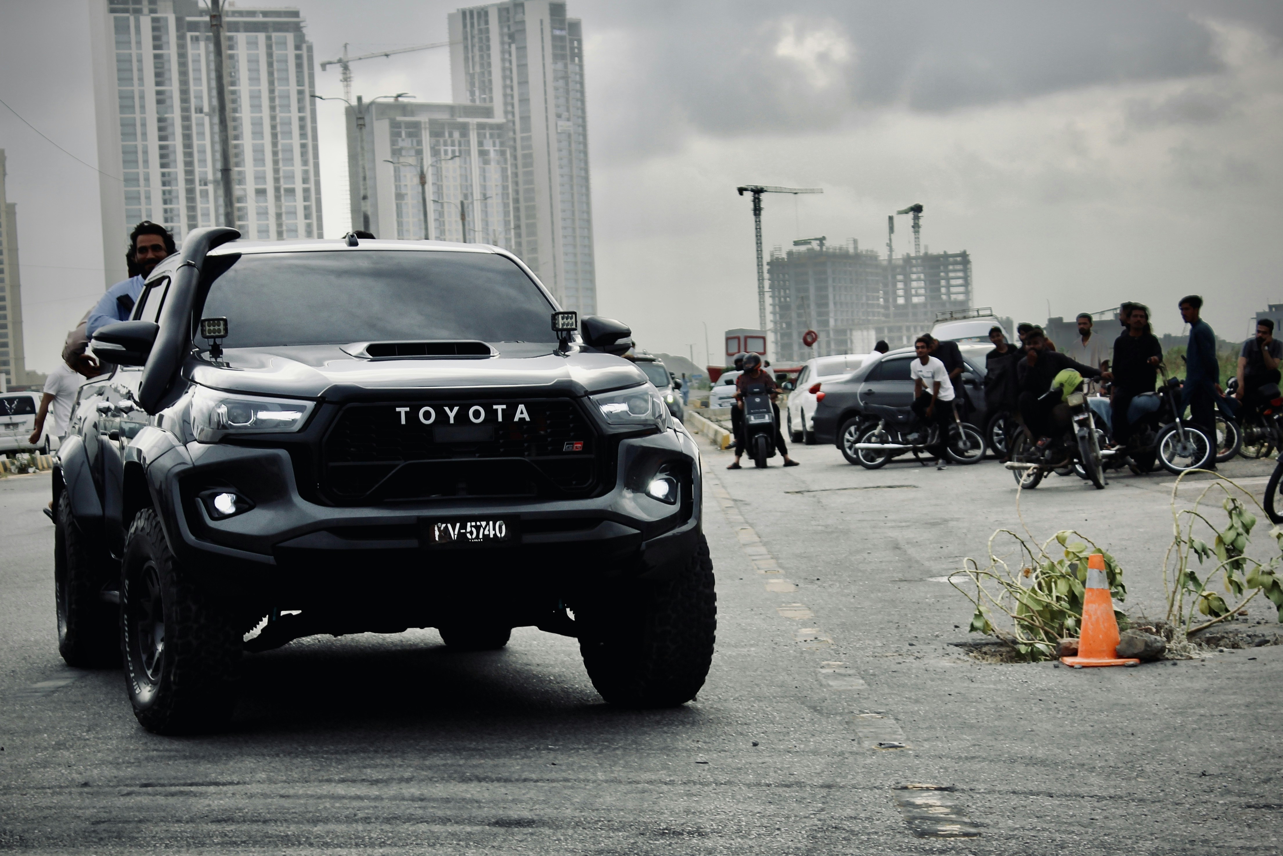 Low-Angle Dominance on a City Street: The Black Toyota and the Rider Assembly