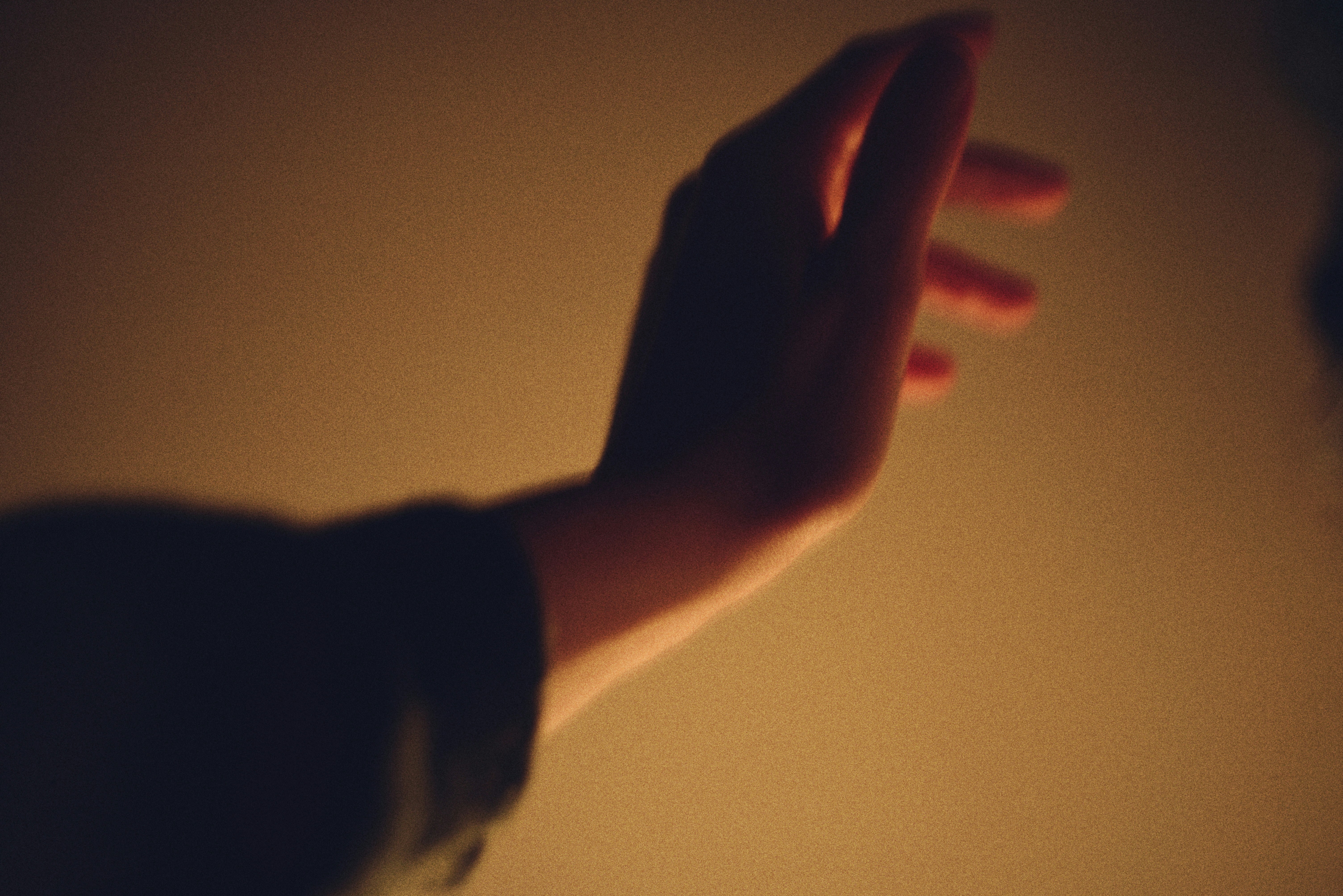 A hand reaching out in warm light.