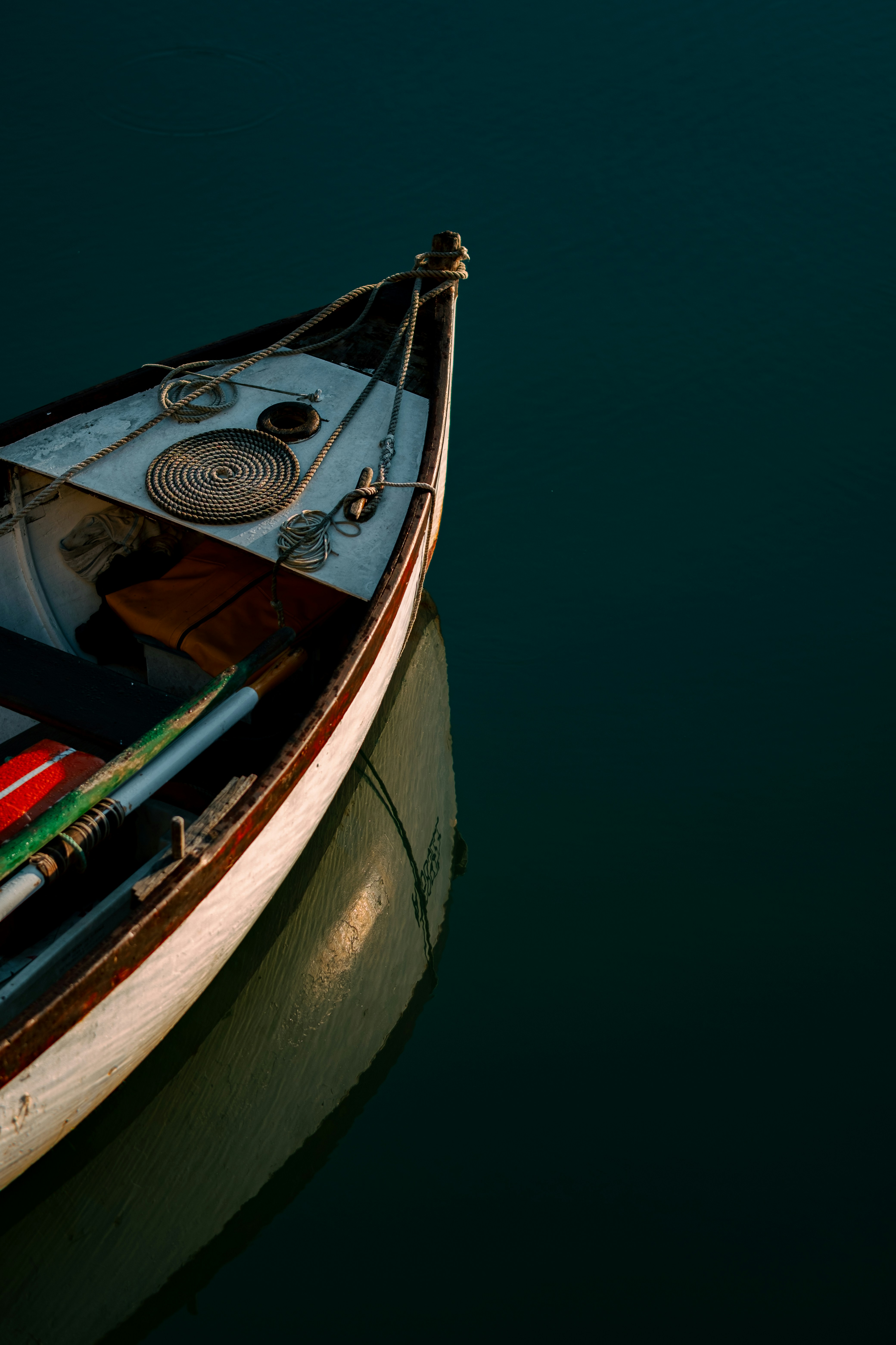 A lone boat floats on dark, still water.
