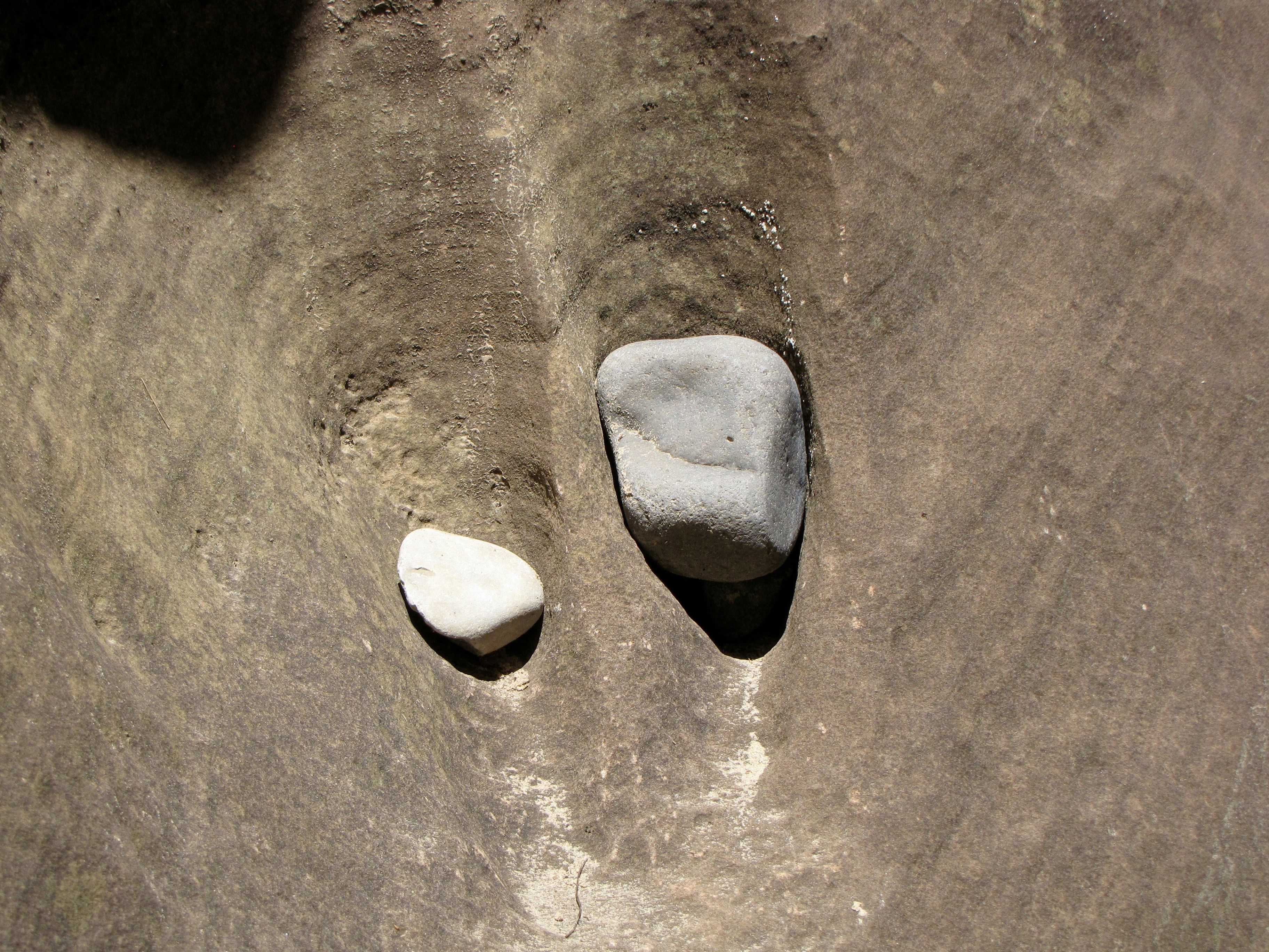 Two smooth stones resting on textured rock surface