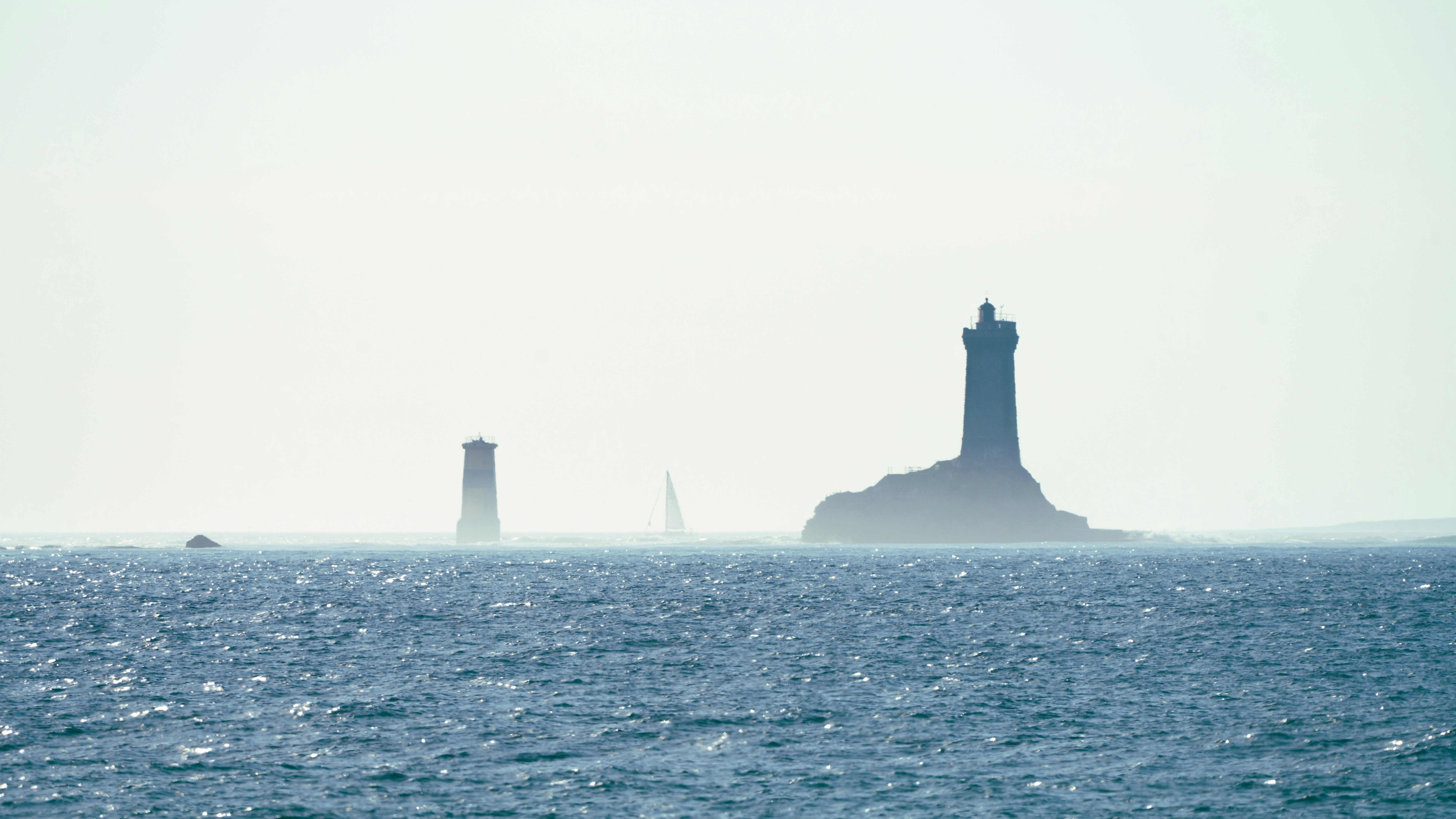 Lighthouses on rocky islands in the ocean.