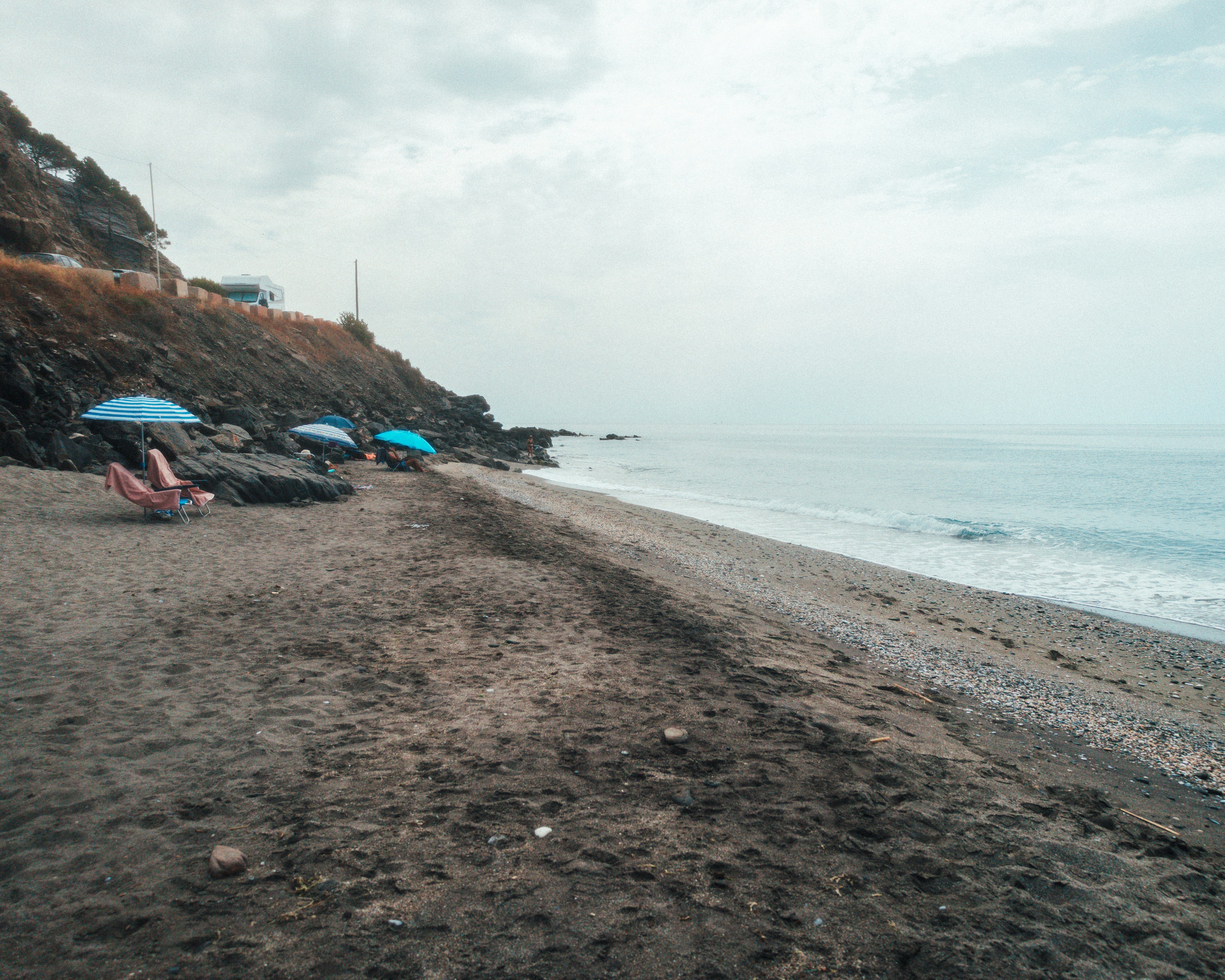 Beach with umbrellas and lounge chairs under cloudy sky
