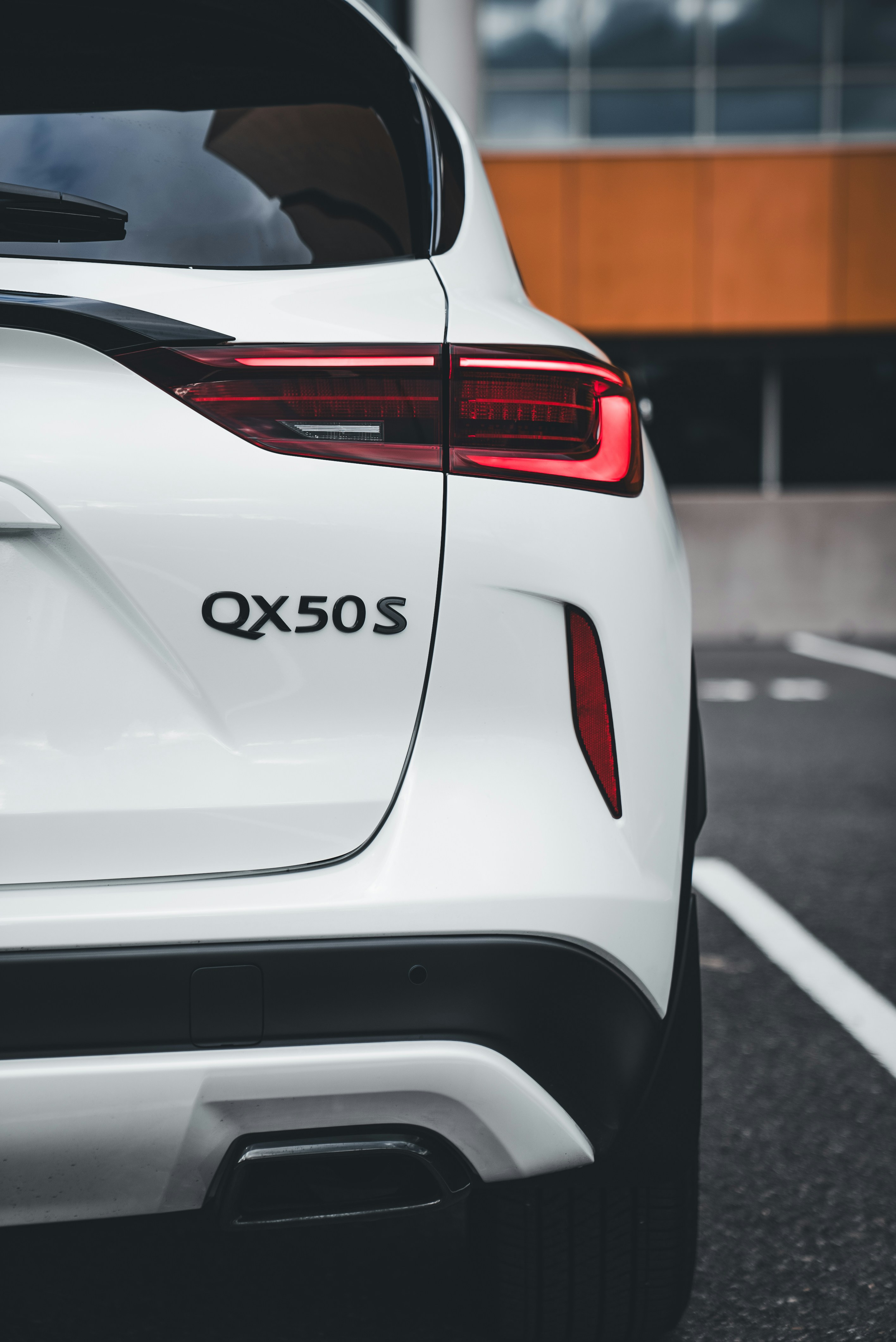 White QX50S in a Parking Lot: Tail-Light Geometry Amid Quiet Asphalt