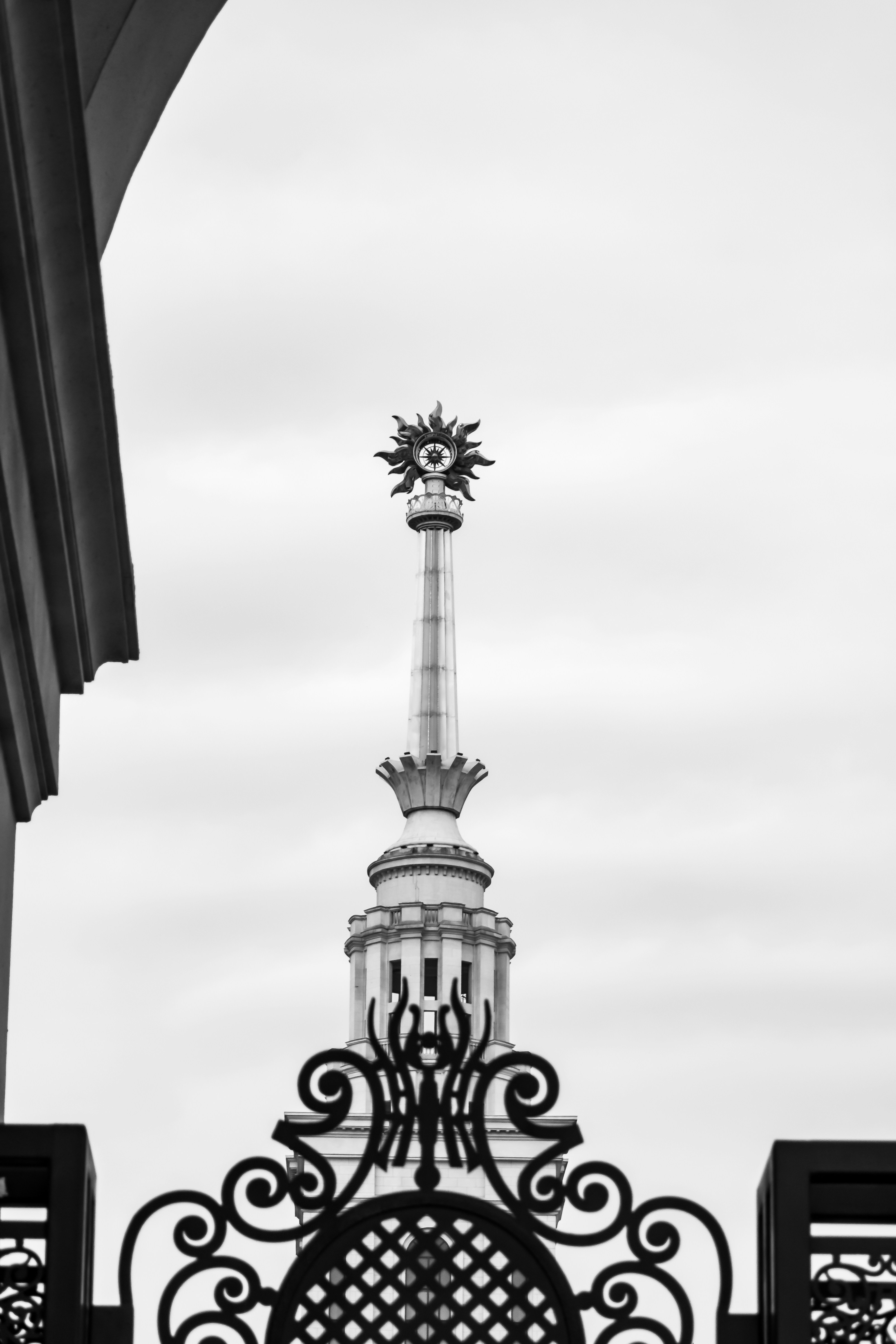 Ornate gate with a tall spire against cloudy sky