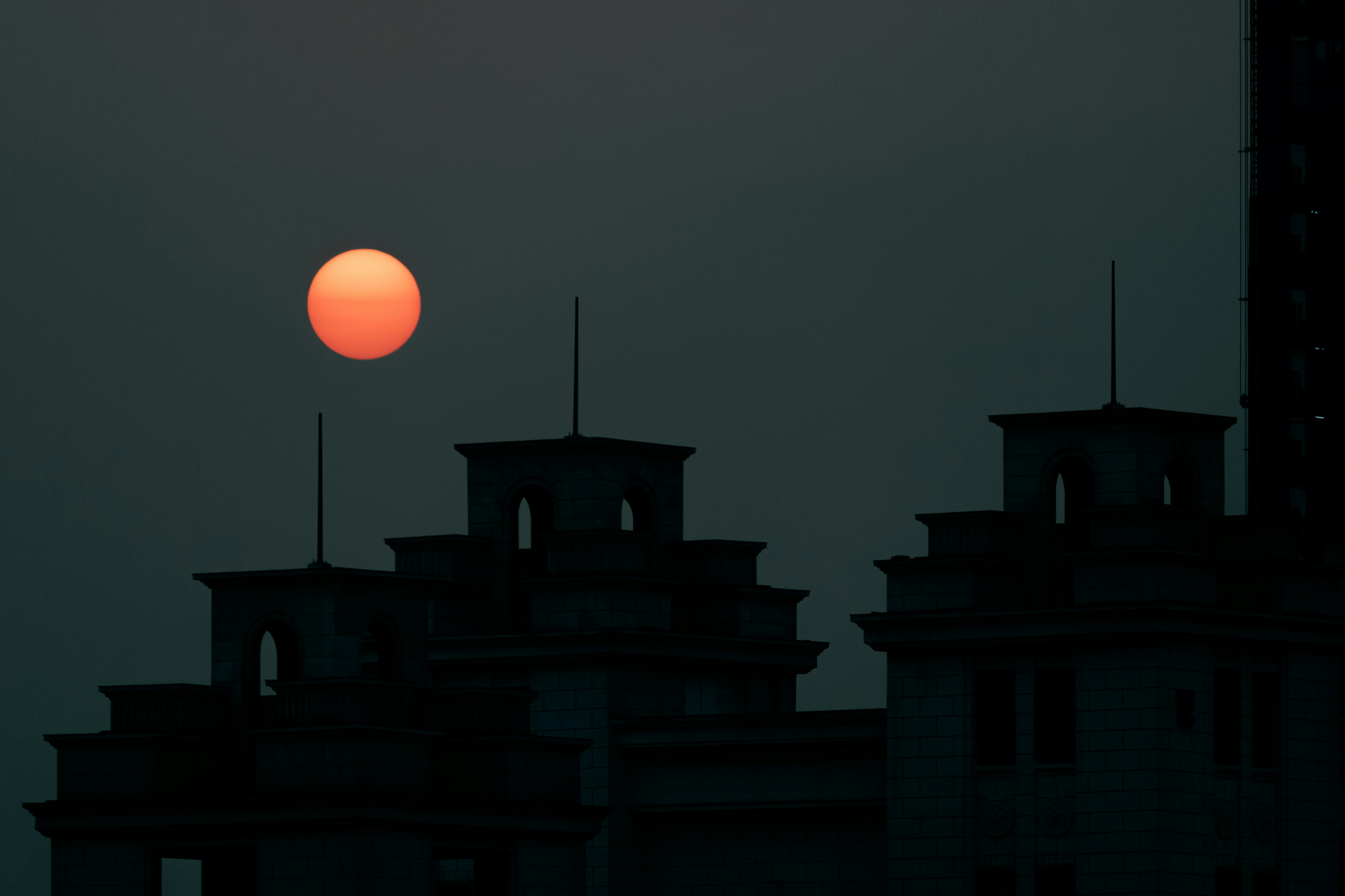 Orange sun setting behind silhouetted buildings