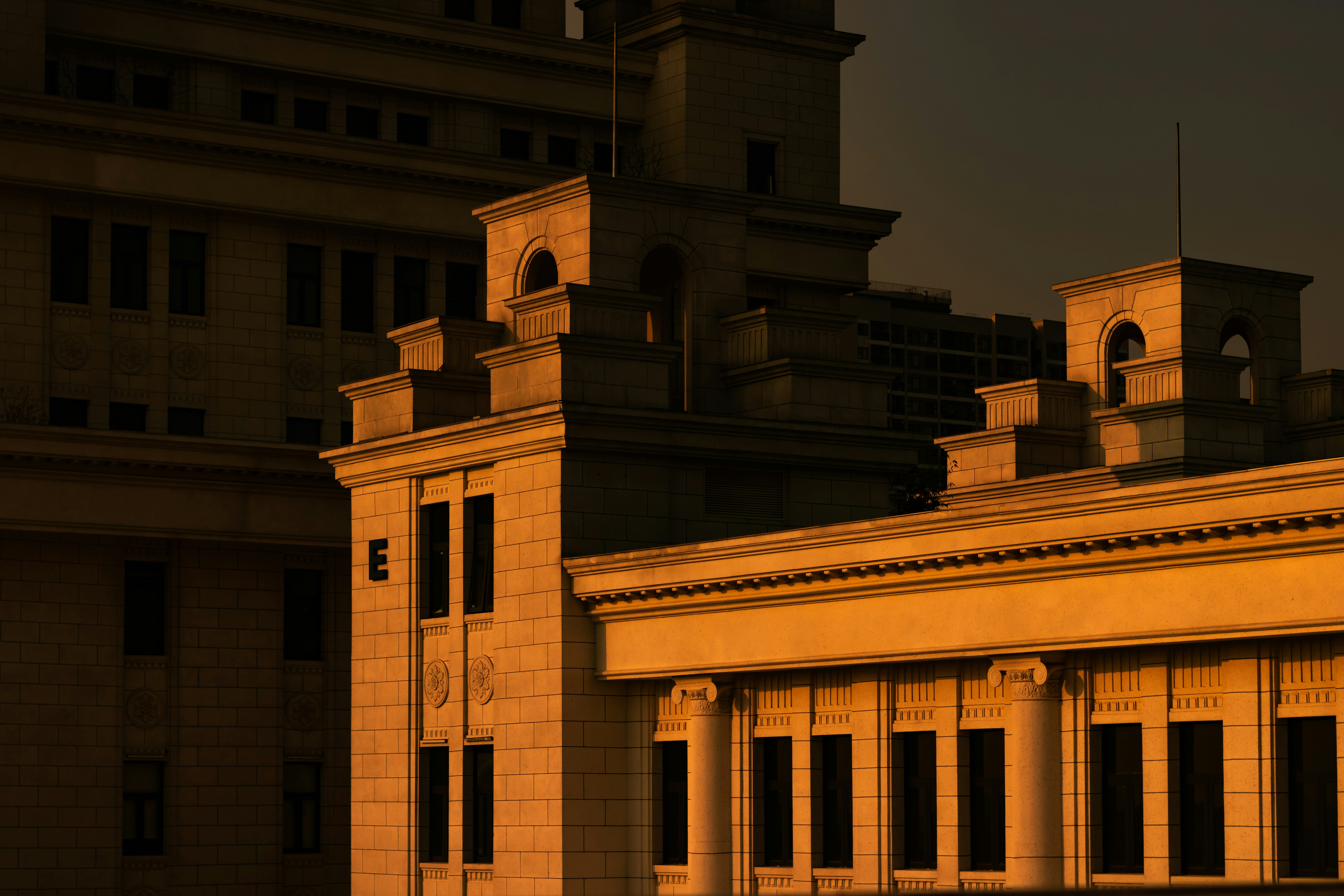 Architectural details of a historic building illuminated by the warm glow of sunset, showcasing intricate stonework and design elements.