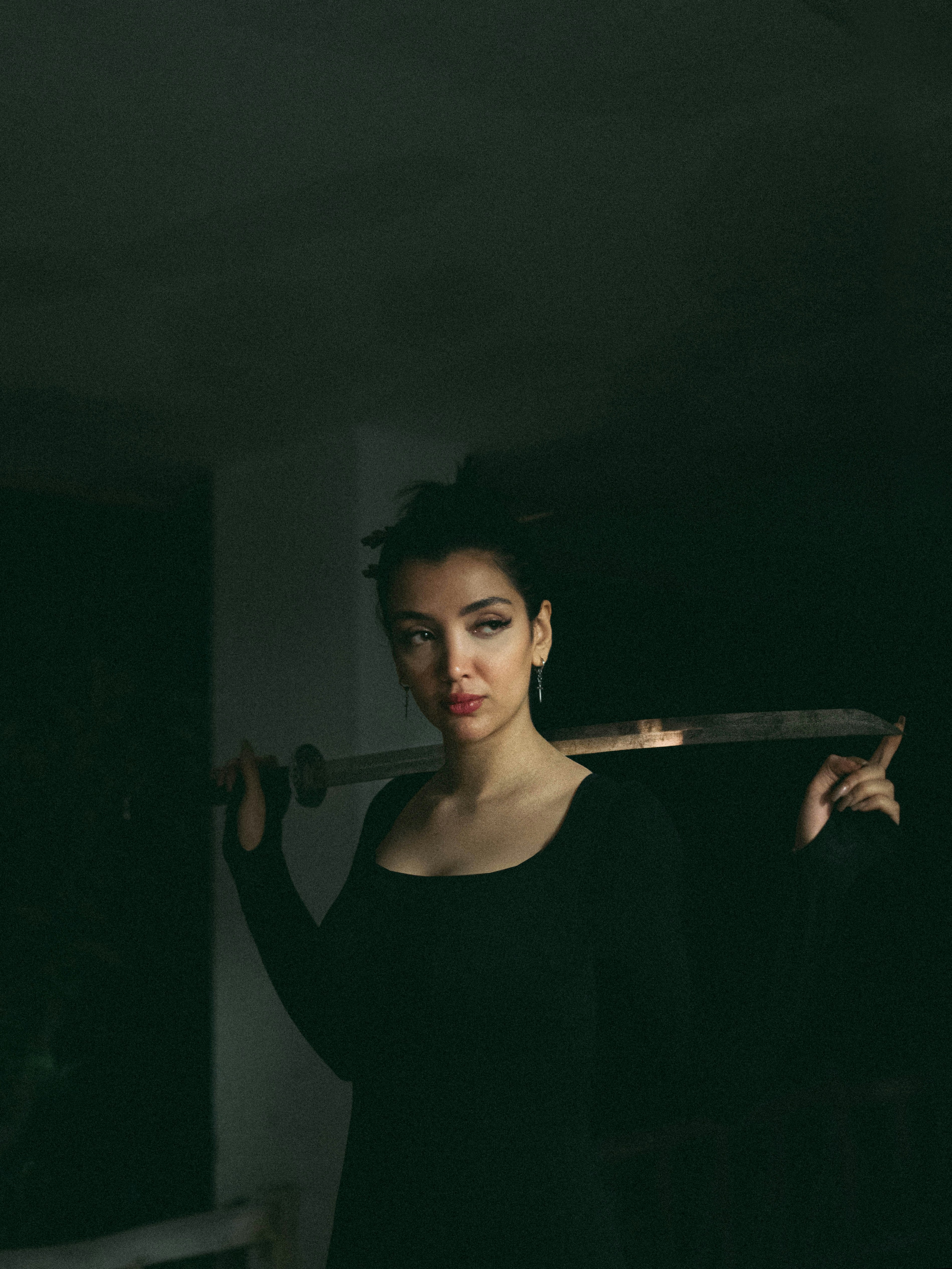Woman in black holding a sword behind her
