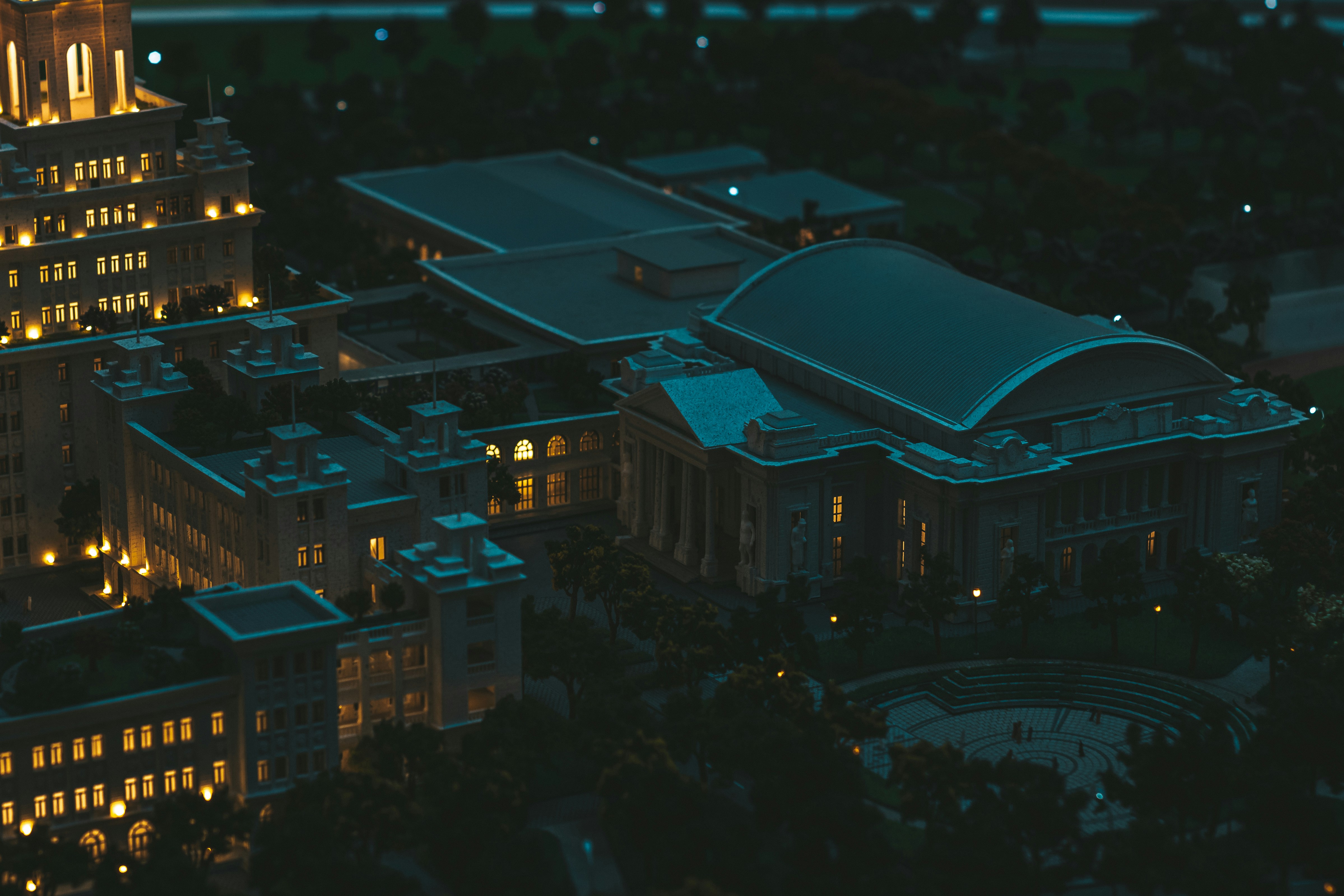 Illuminated building complex at night with distant lights.
