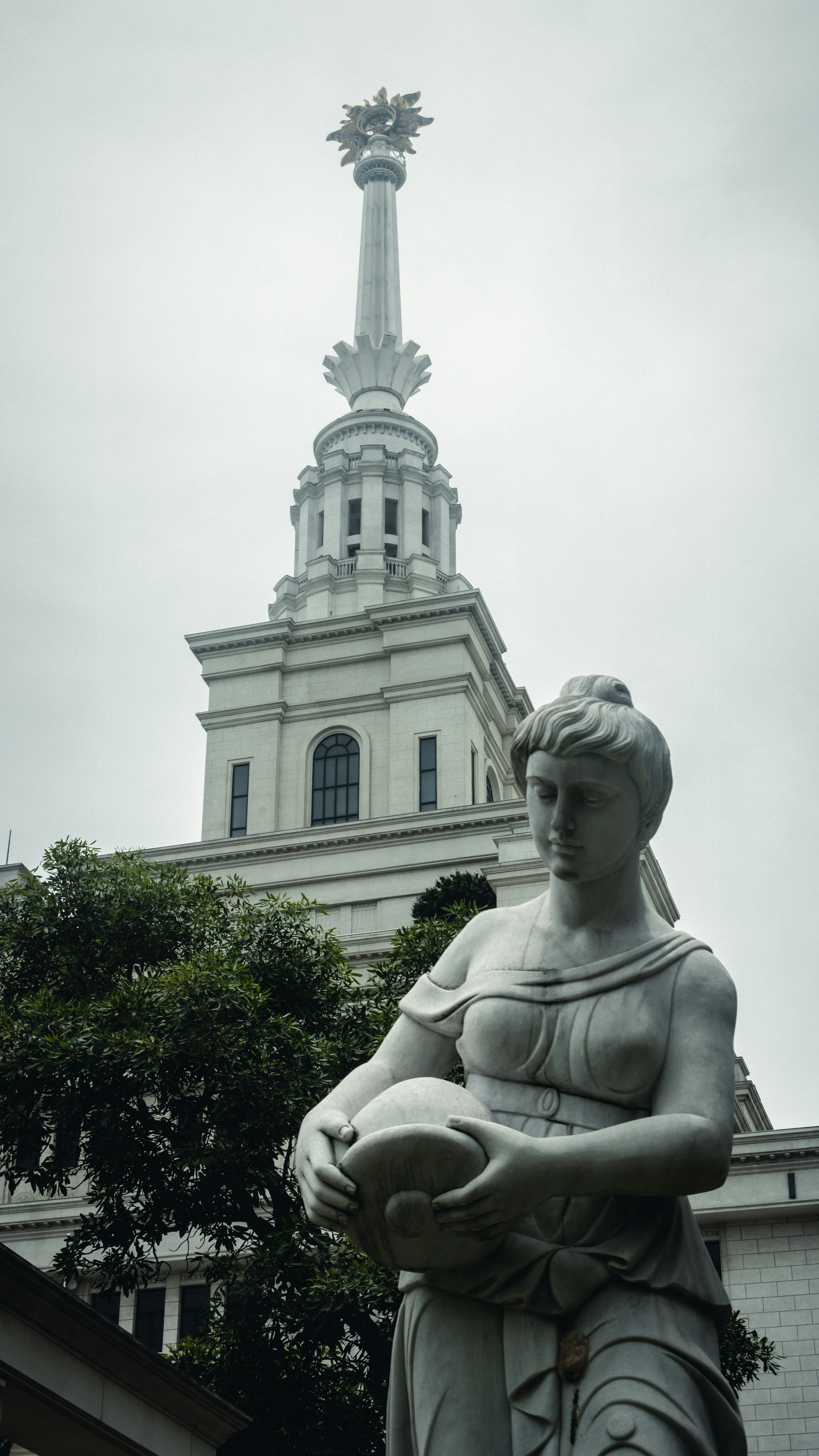 Stone statue of woman holding sphere before building