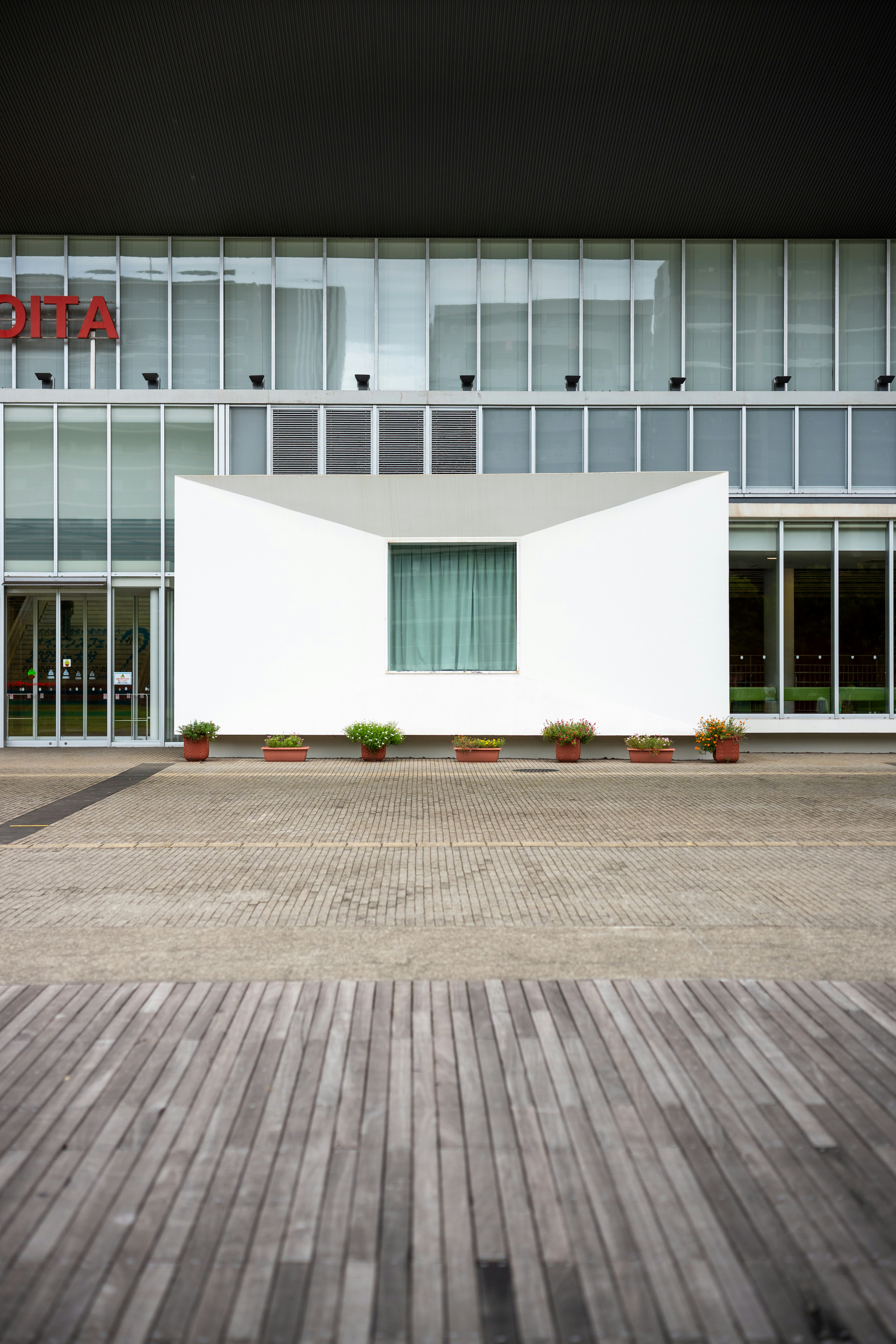Modern white building facade with large windows and plants