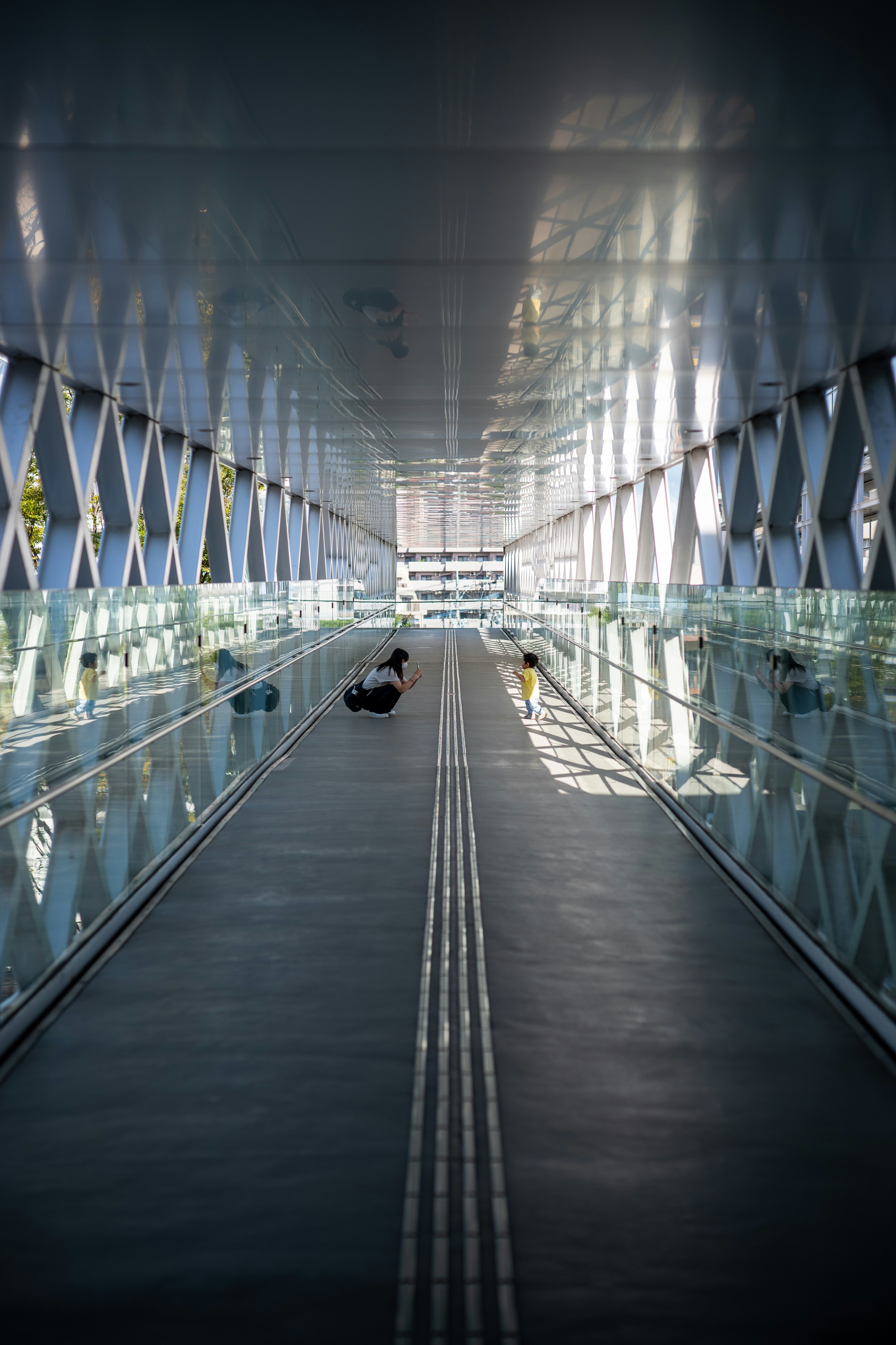 Two people walking in a modern glass walkway