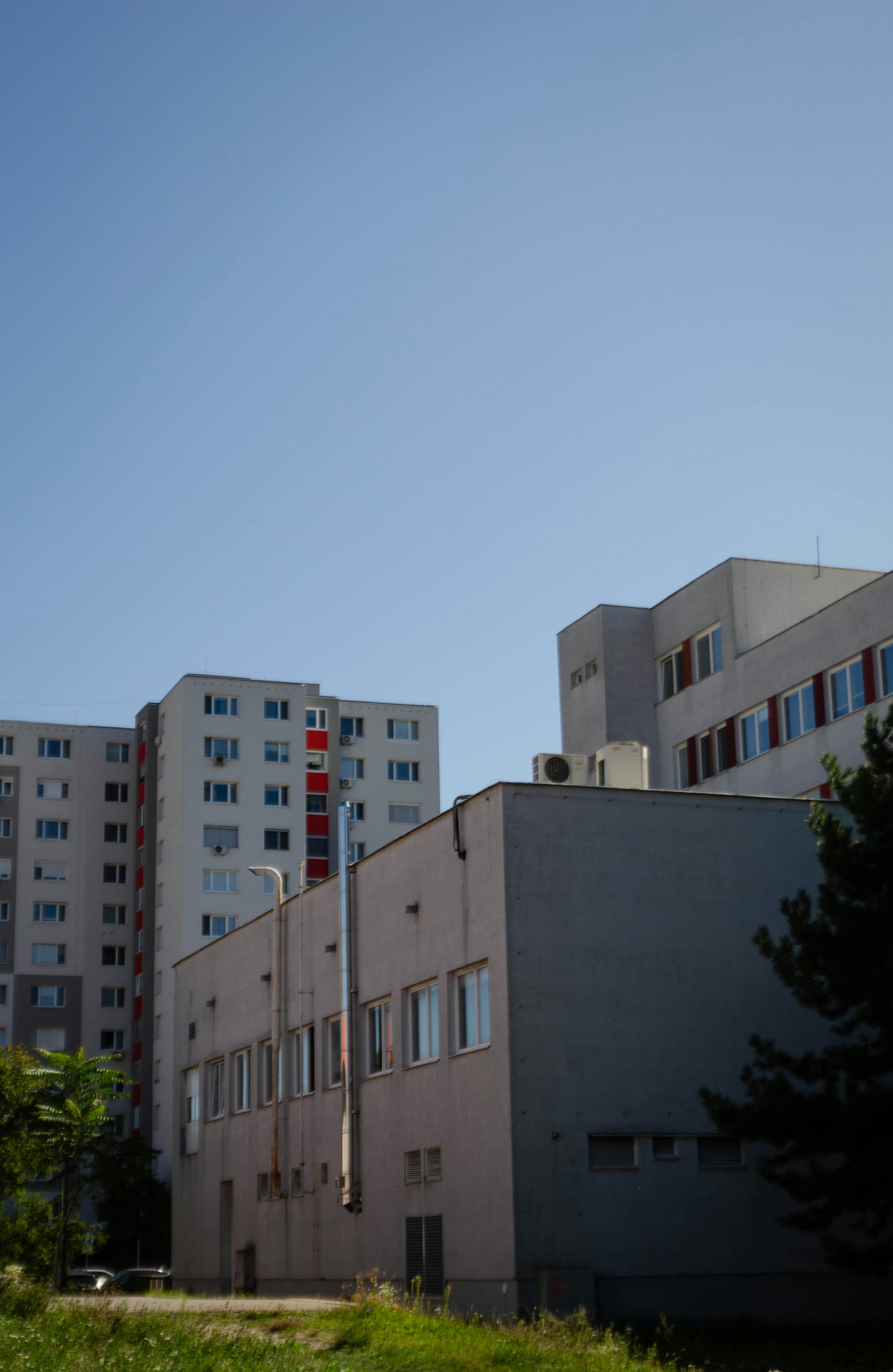 Red Vertical Rhythm Over Gray Facades Under a Cerulean Sky