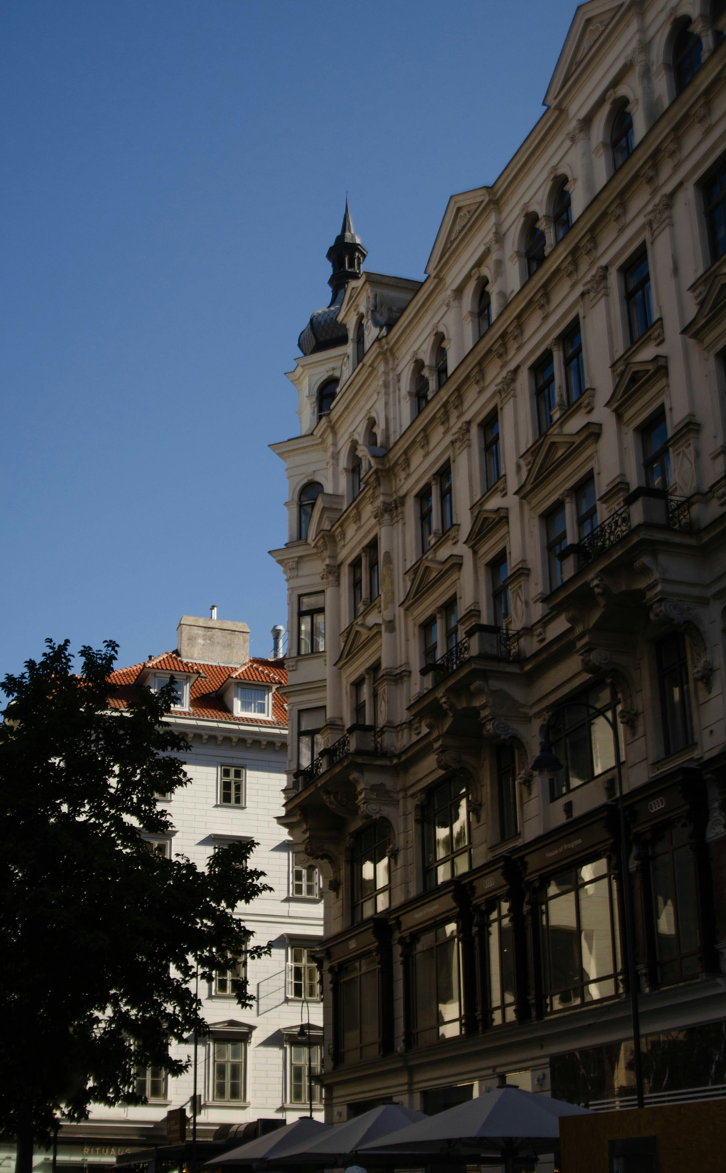 Elegant buildings with intricate facades and a clear blue sky create a striking urban scene. The interplay of light and shadow highlights architectural details.