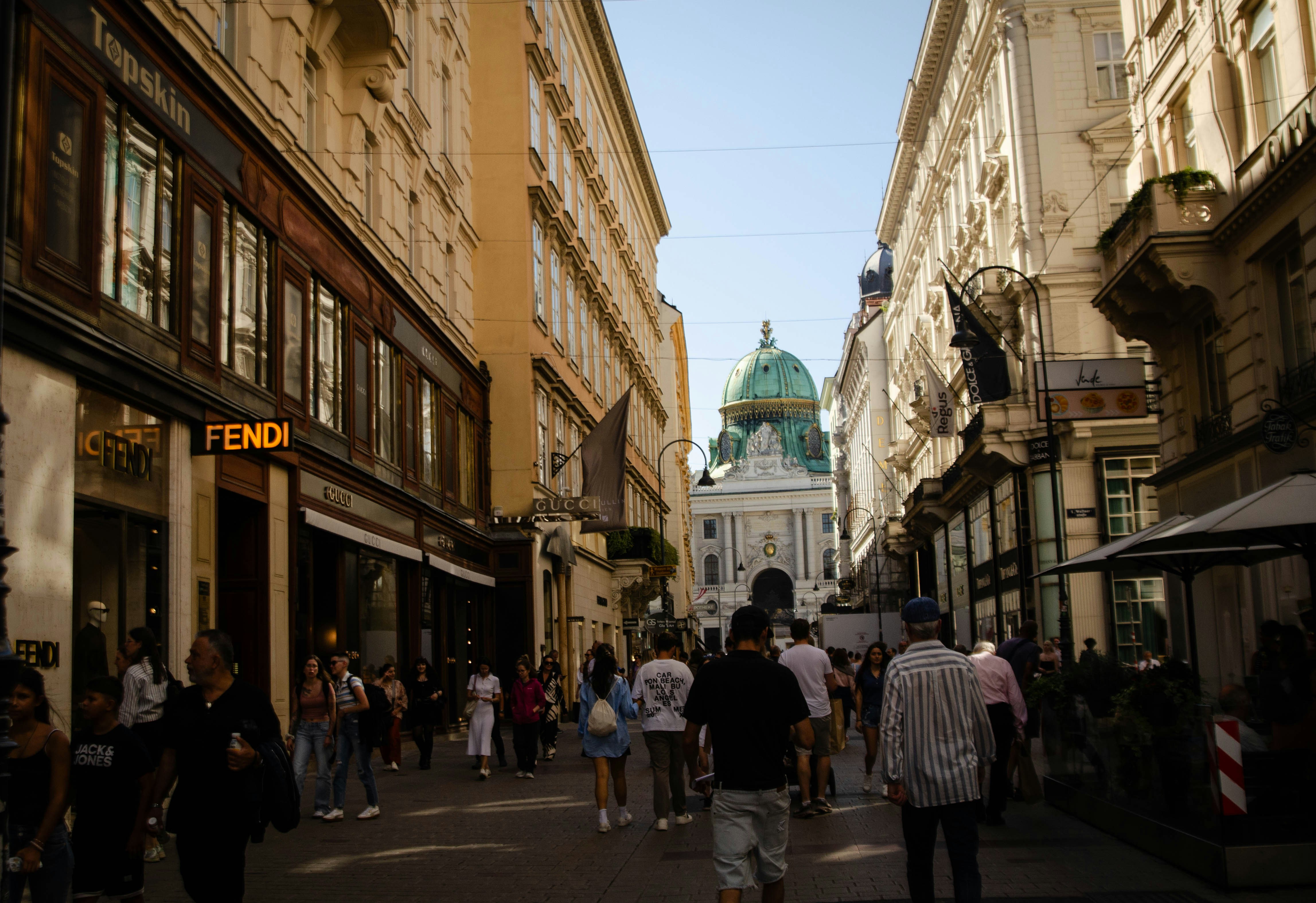People walking down a european street with dome building.