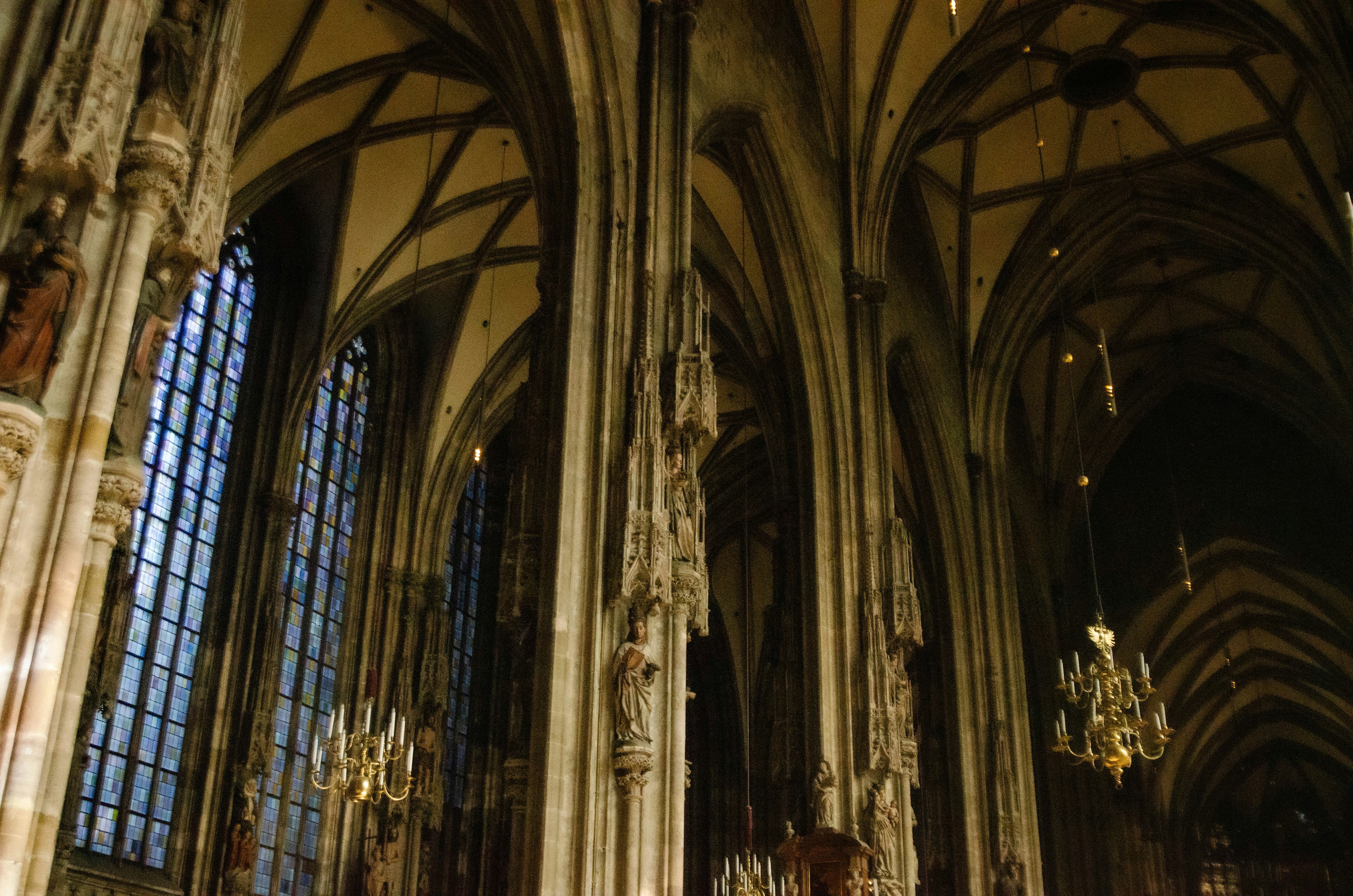 Intricate Gothic architecture with towering arches and stained glass windows illuminating the interior of a historic cathedral.