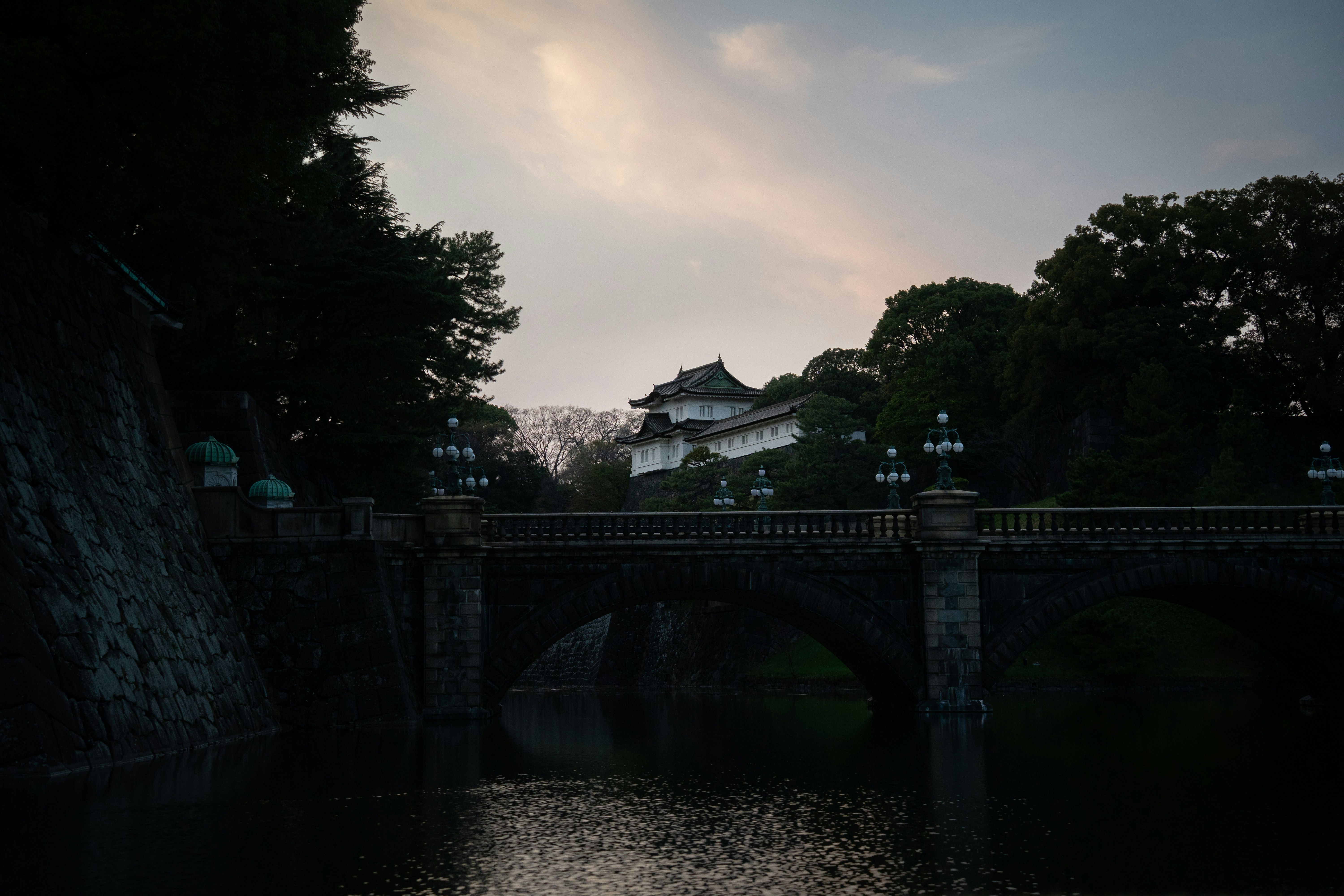 Precisely a photo of Fushimi-yagura, one of the buildings in the Imperial Palace complex, Tokyo. | Bridge leading to traditional japanese palace at dusk