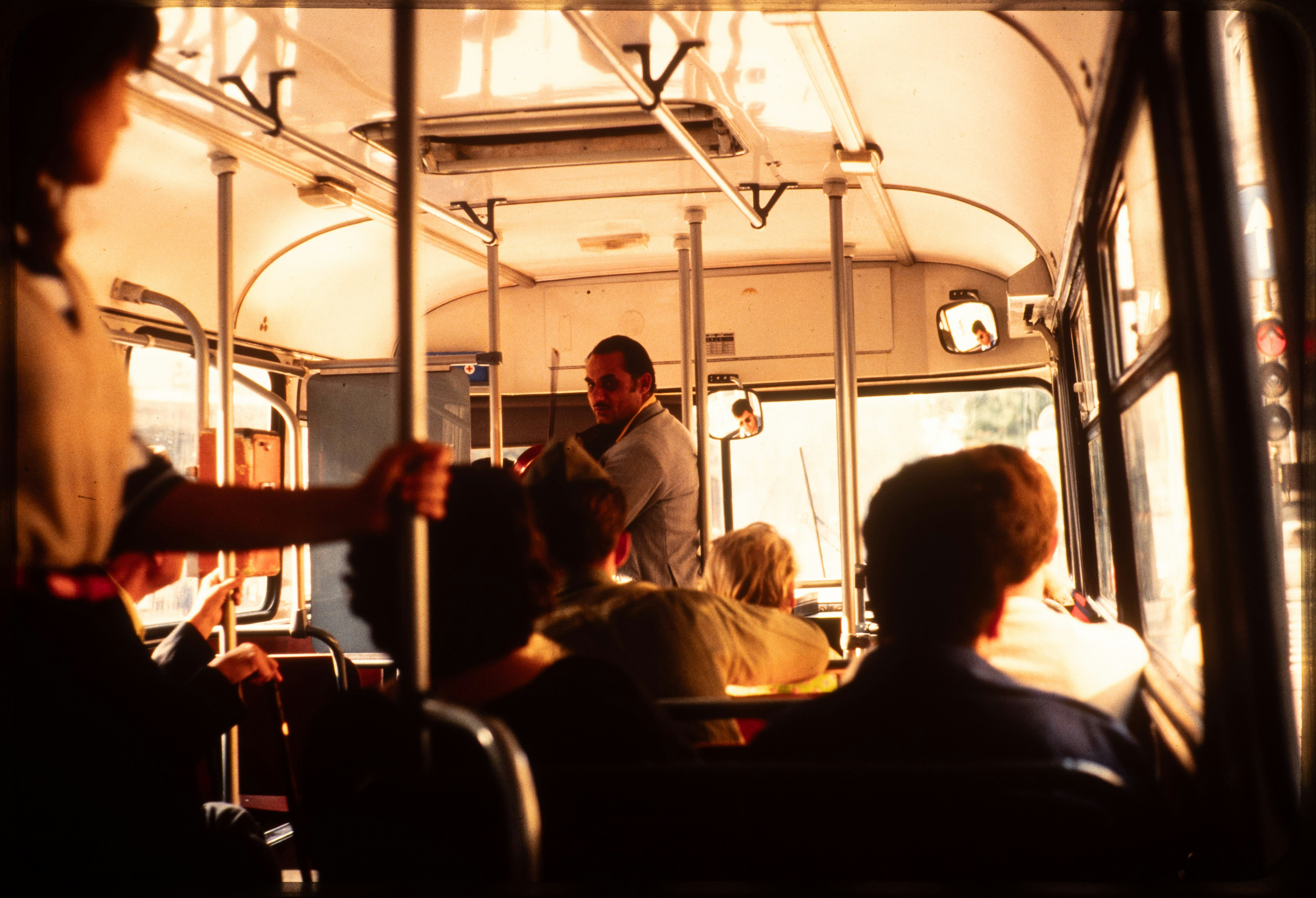 A Quiet Moment in Amber Light: Standing Figure Anchors a Bus Interior